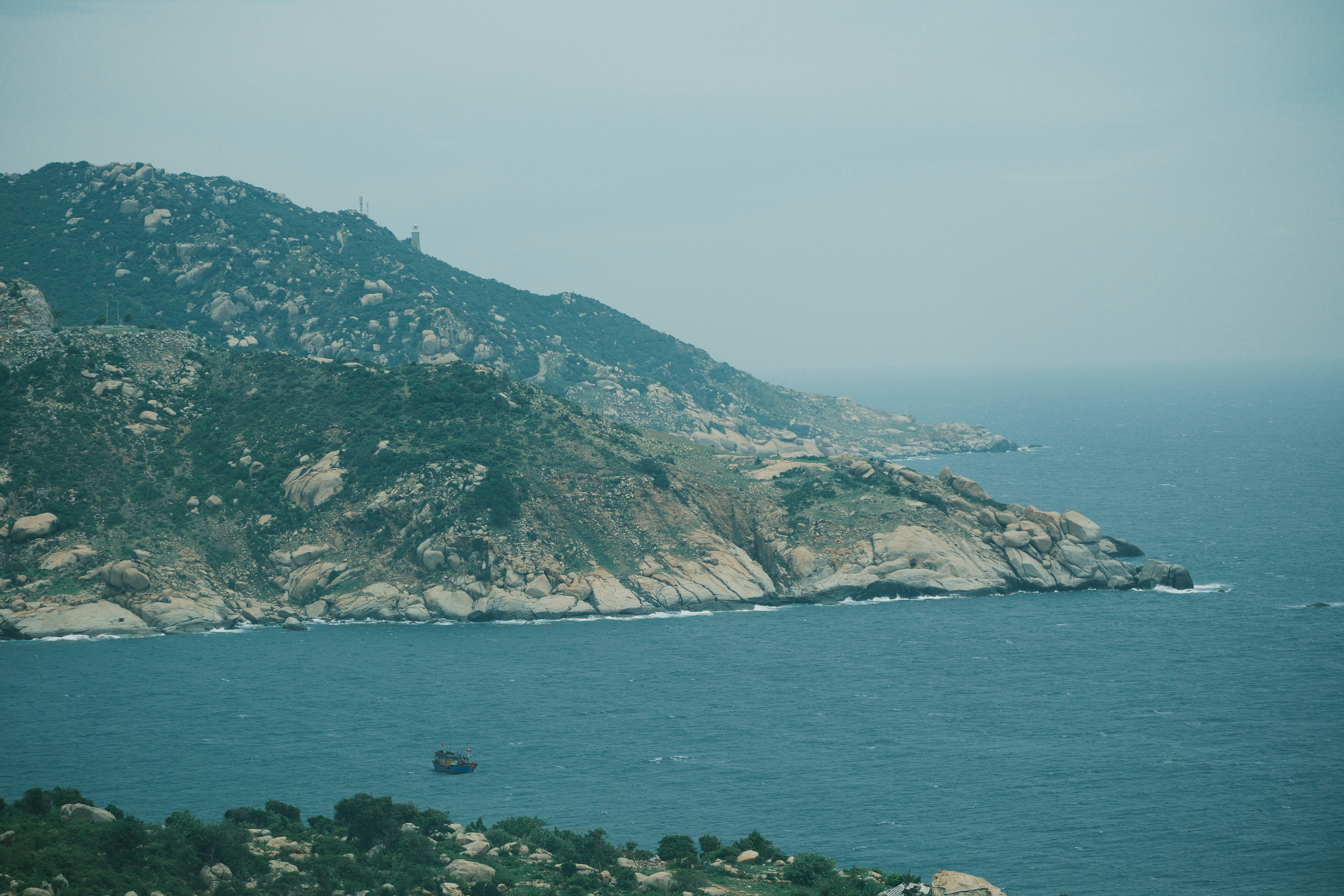 Rocky coastline with blue ocean under a hazy sky