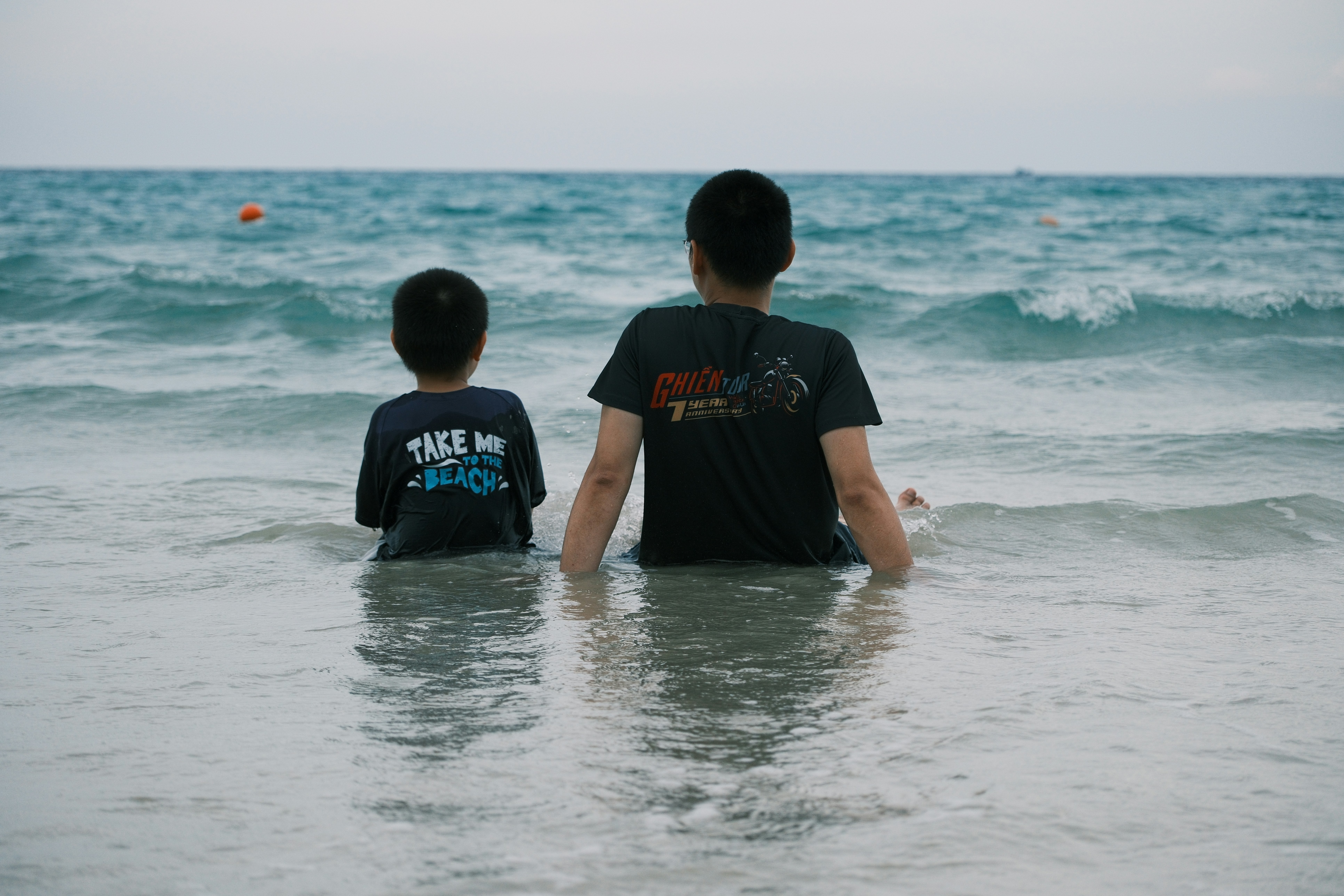 Two boys sitting in the ocean waves