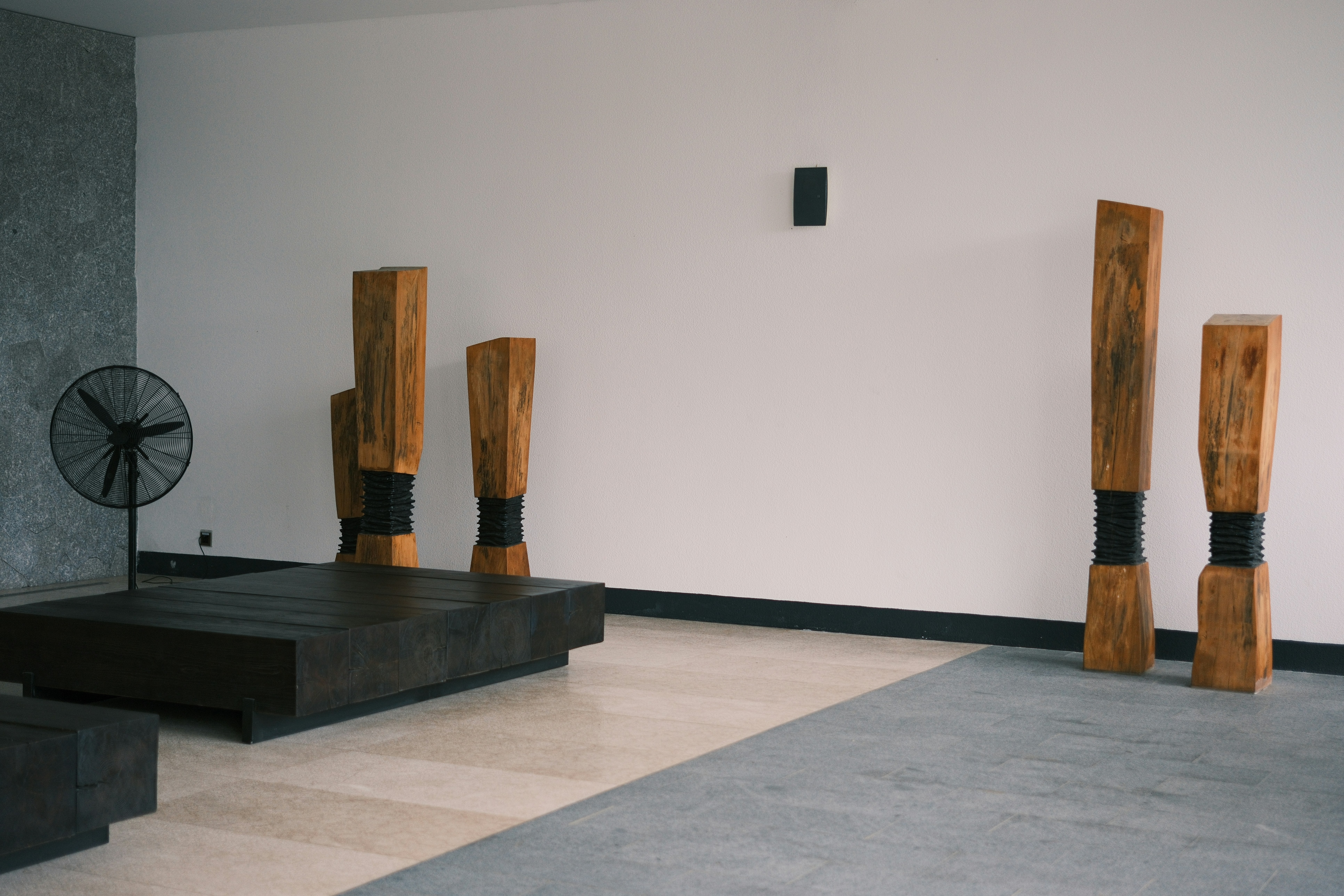 Wooden sculptures and a fan in a modern room.