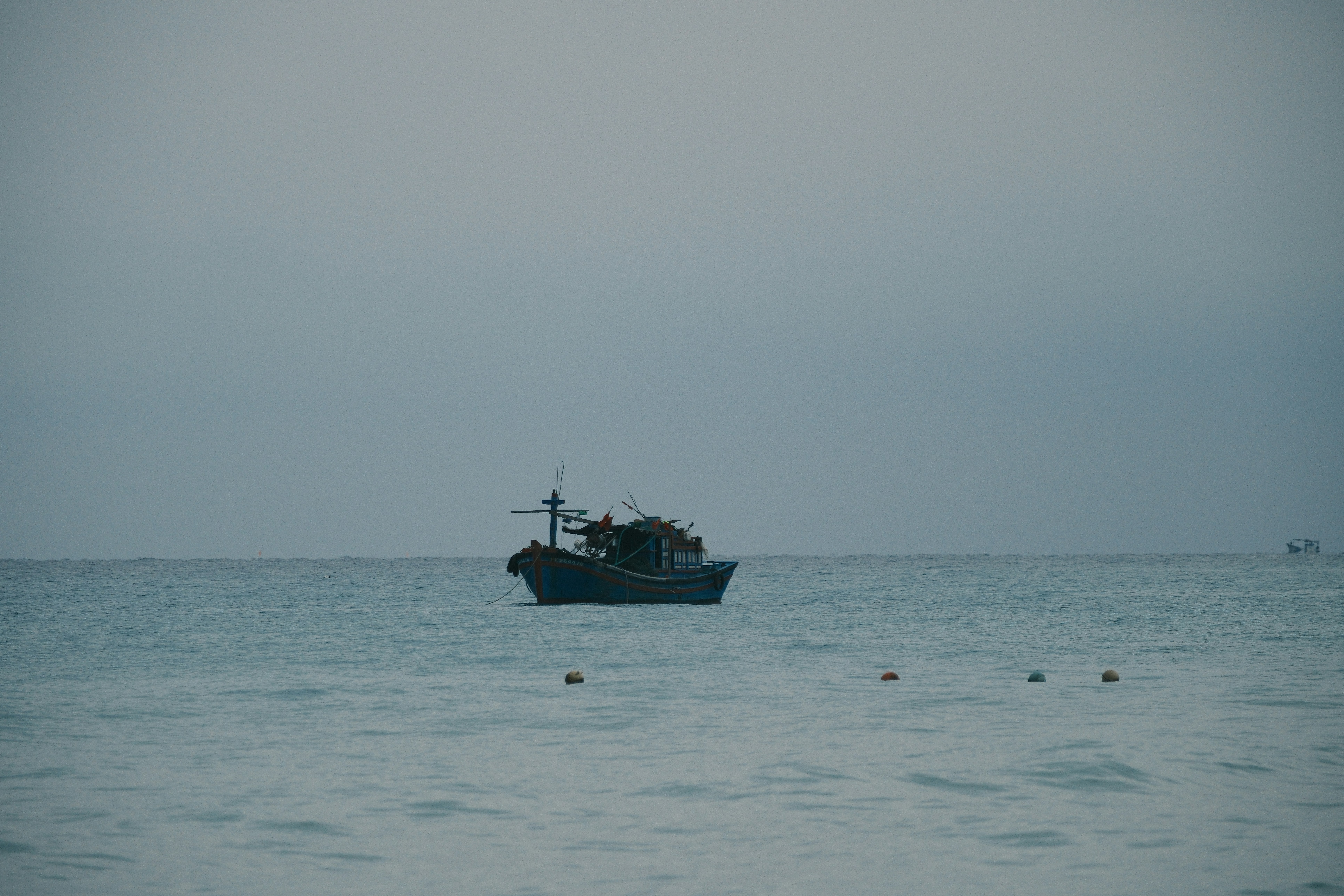 A lone fishing boat sails on a calm sea.