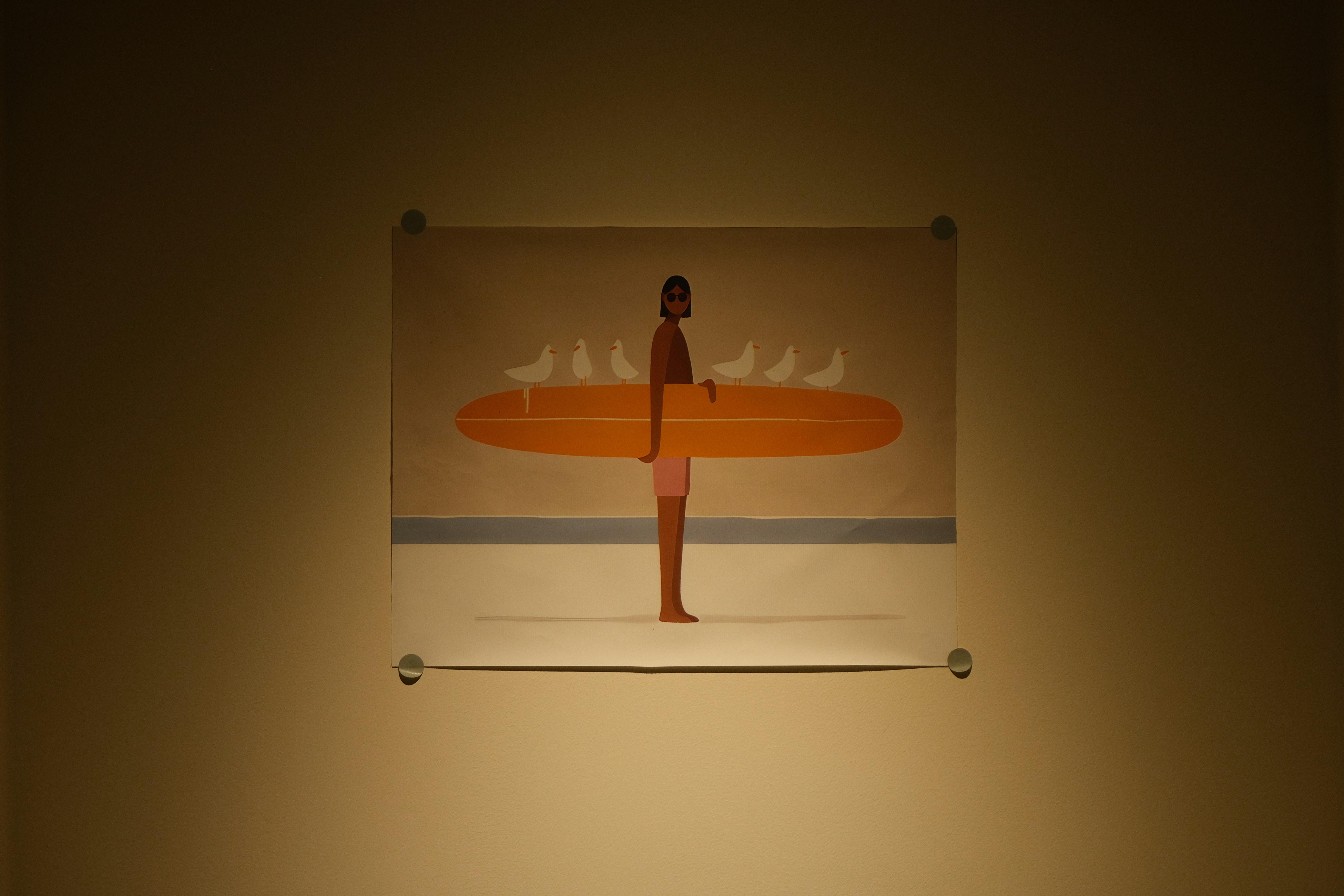 Person standing by surfboard with birds.