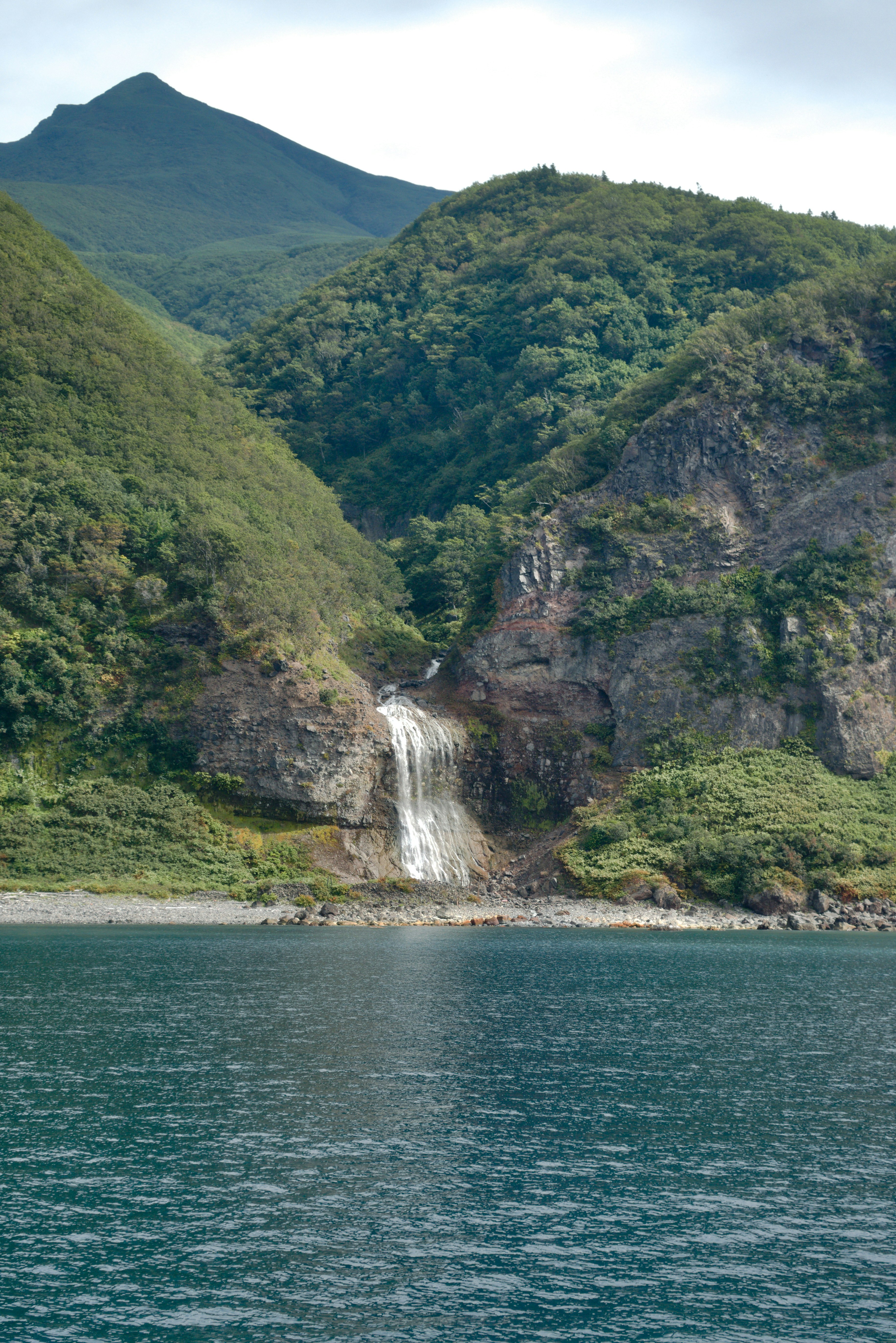 Cliffside Cascade: Green Ridges Framing a Seaside Waterfall