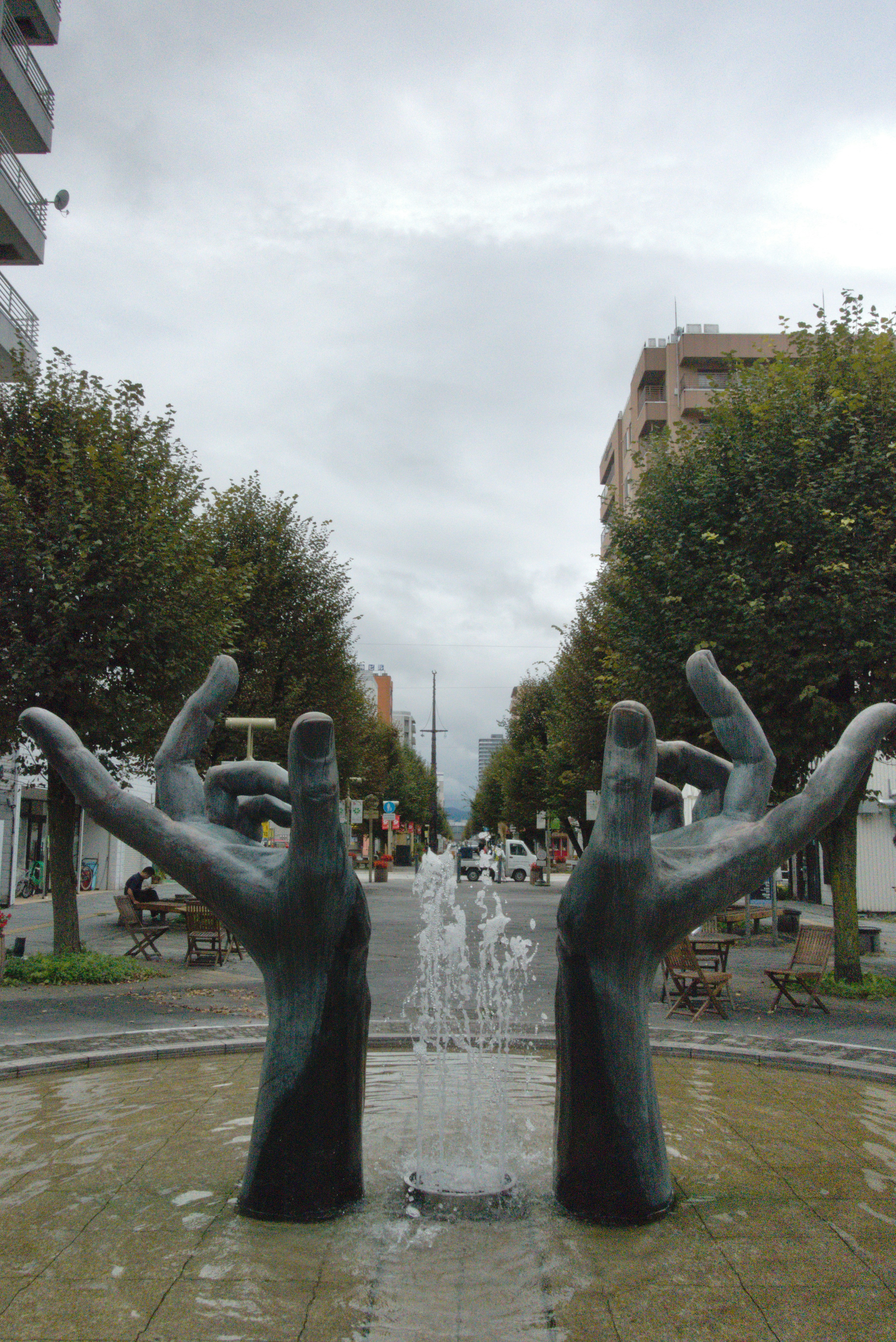 Sculpture of two hands with fountain in city street