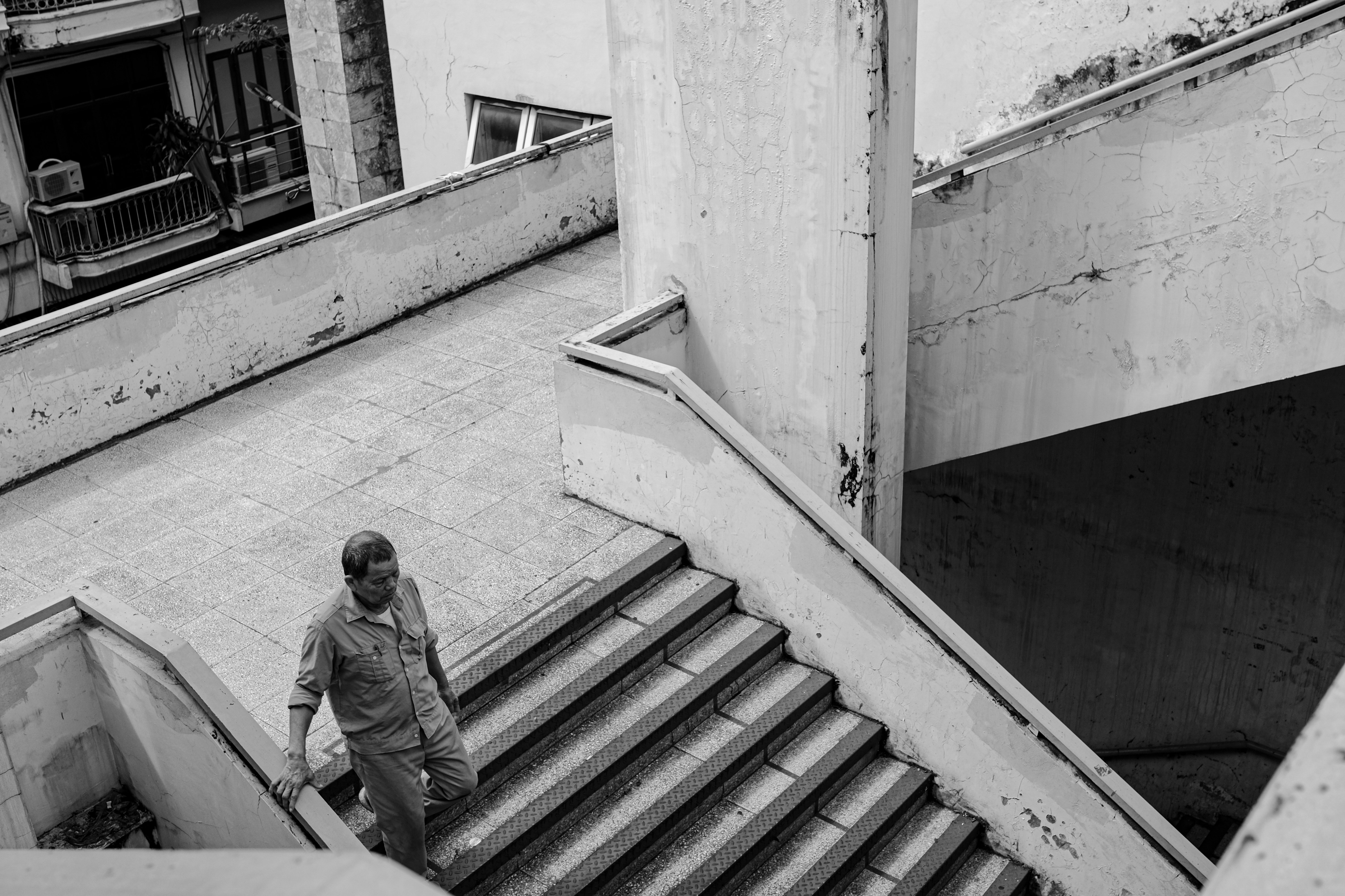 Man walking down concrete stairs in urban setting.