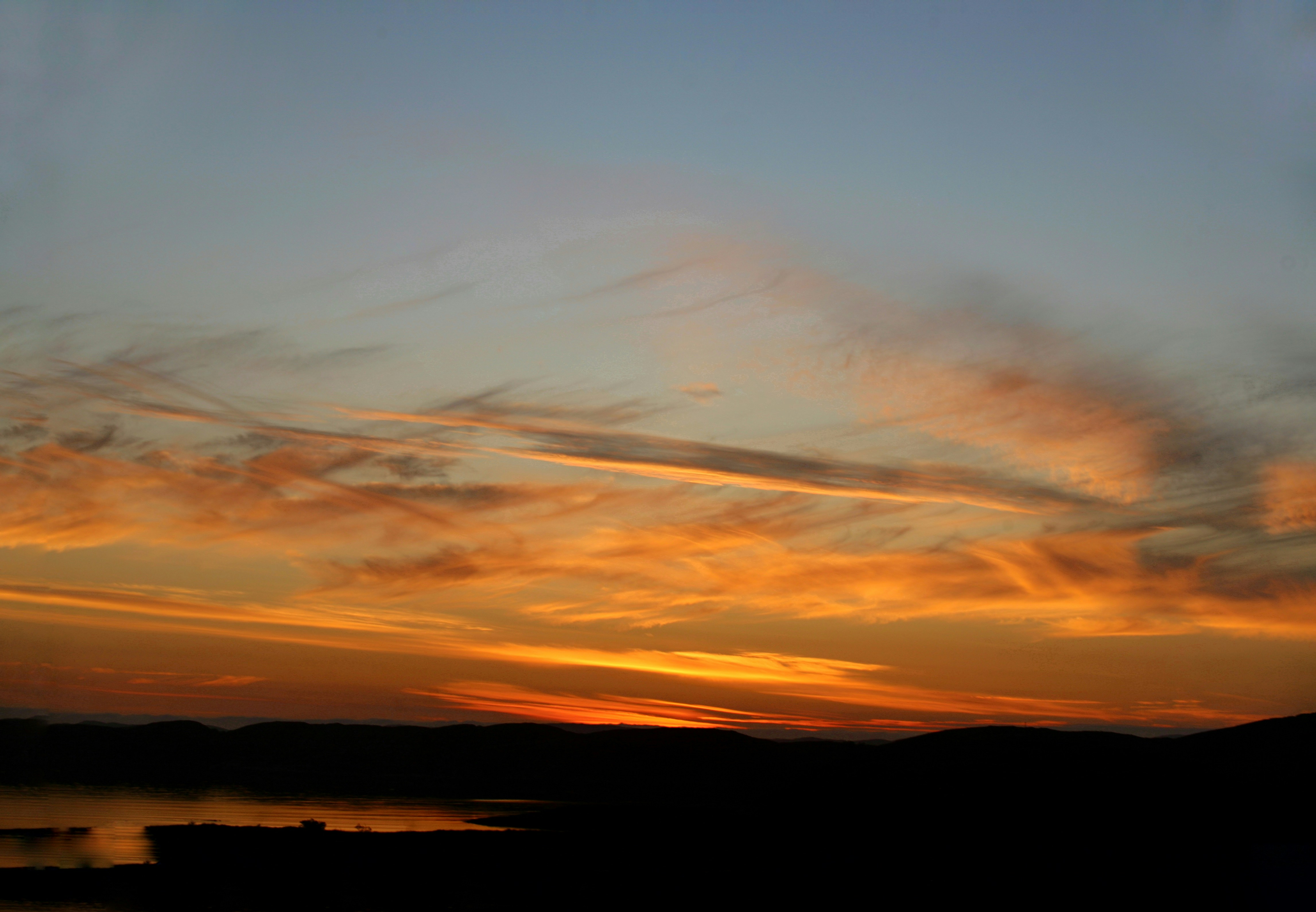 Colorful sunset above the darkness | Vibrant sunset clouds over dark landscape and water