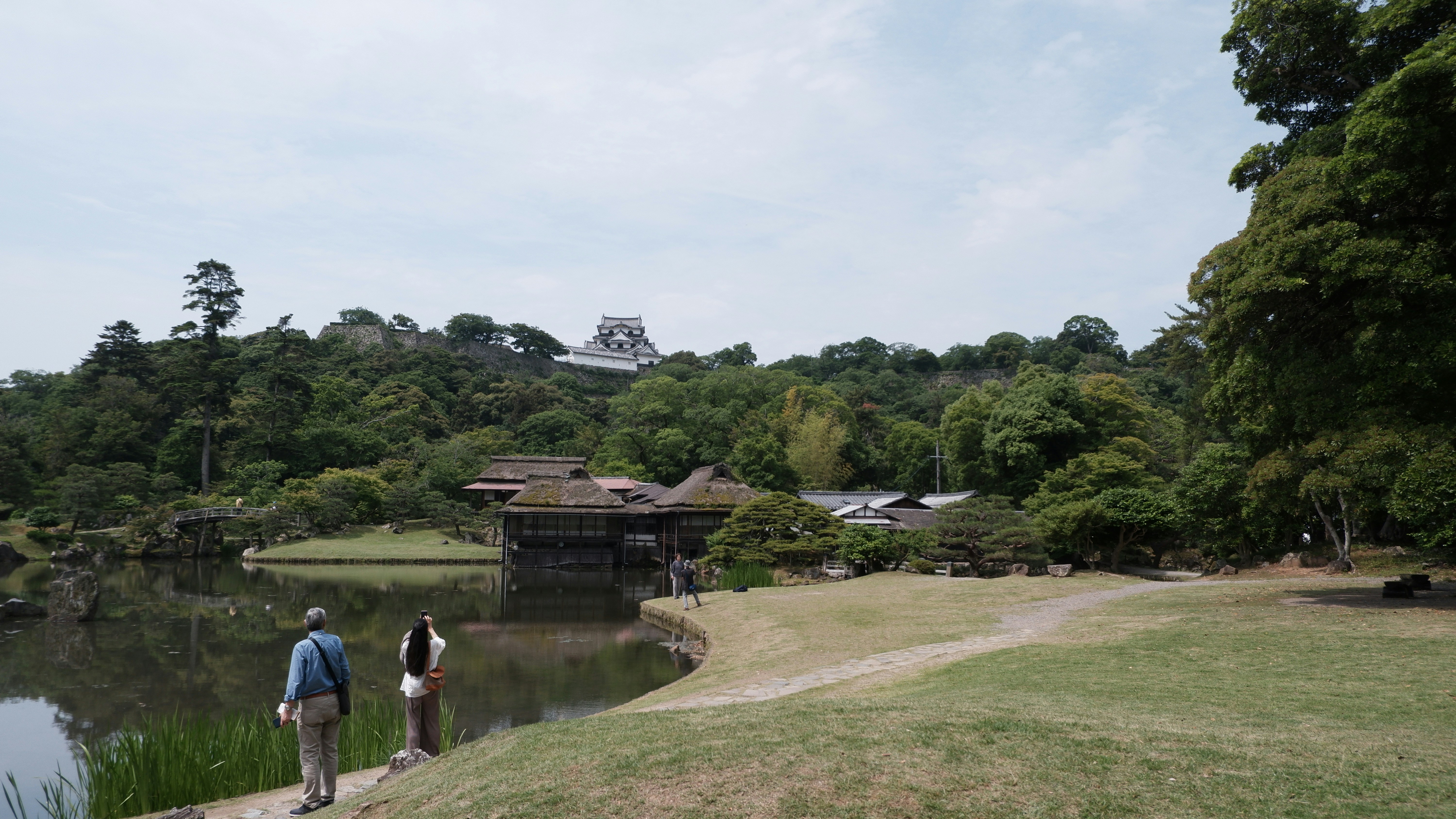Pondside Calm: Two Visitors with a Distant Hilltop Castle
