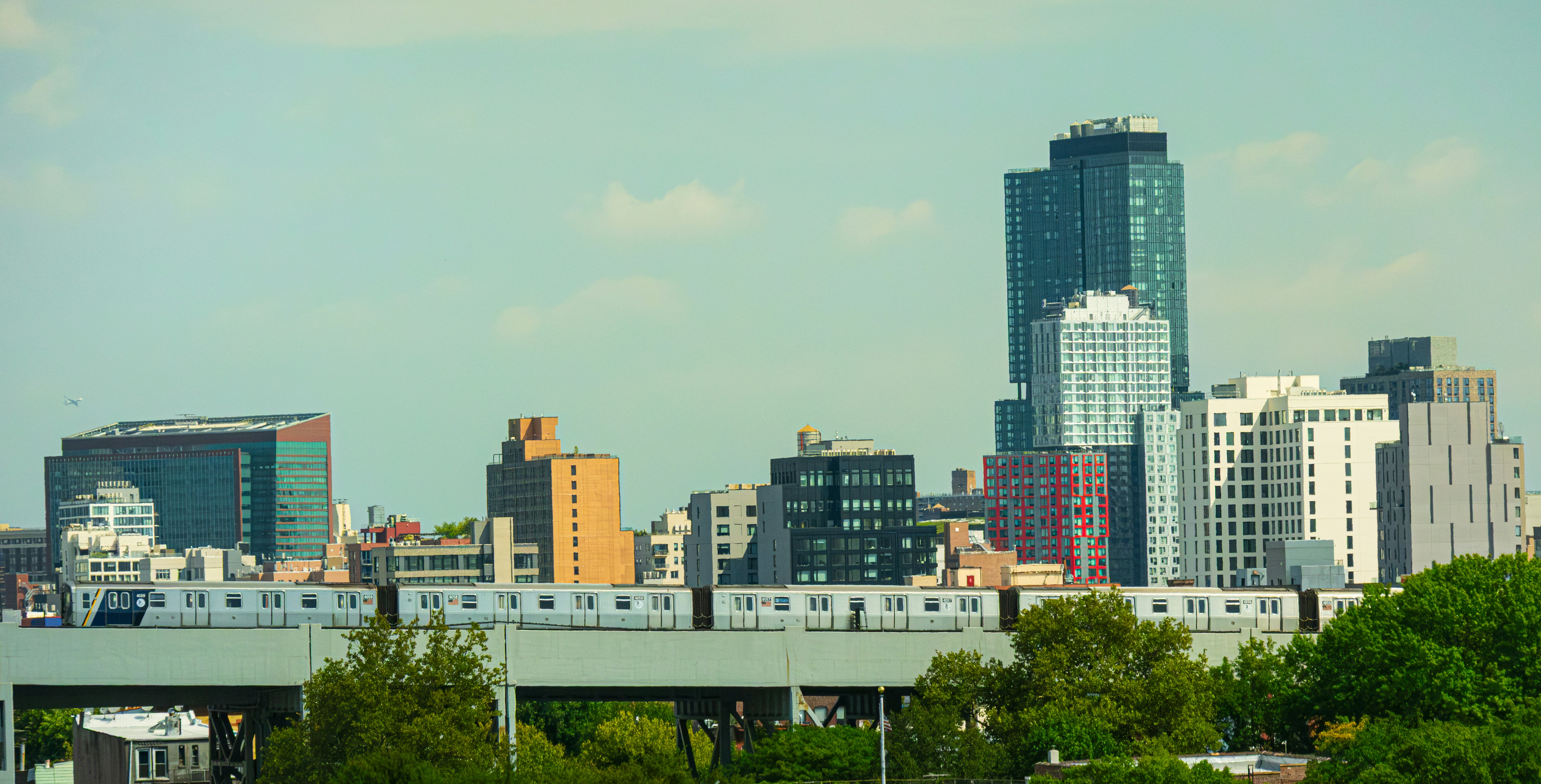 Train travels across elevated tracks with city skyline.