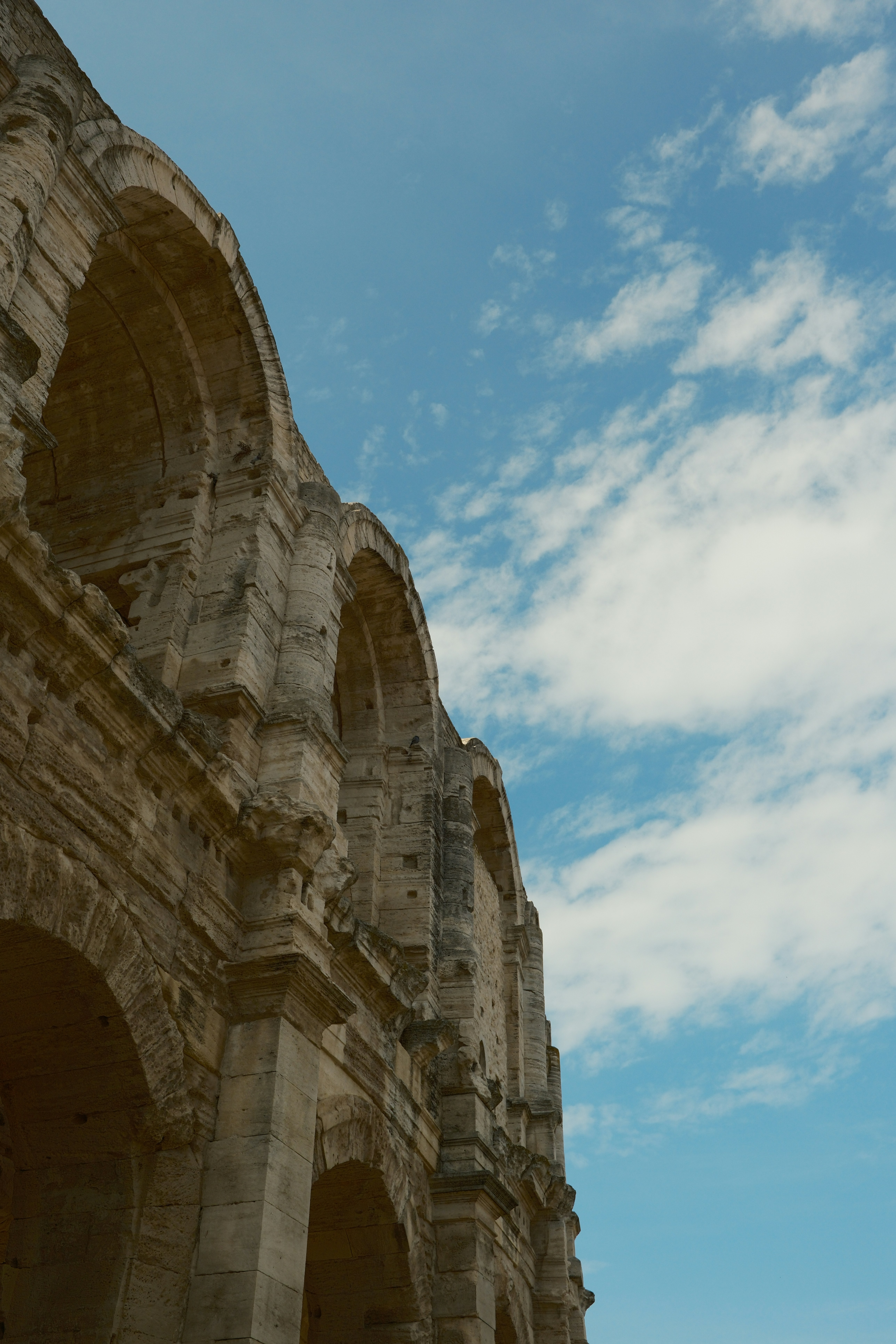Ancient stone arches against a cloudy blue sky.