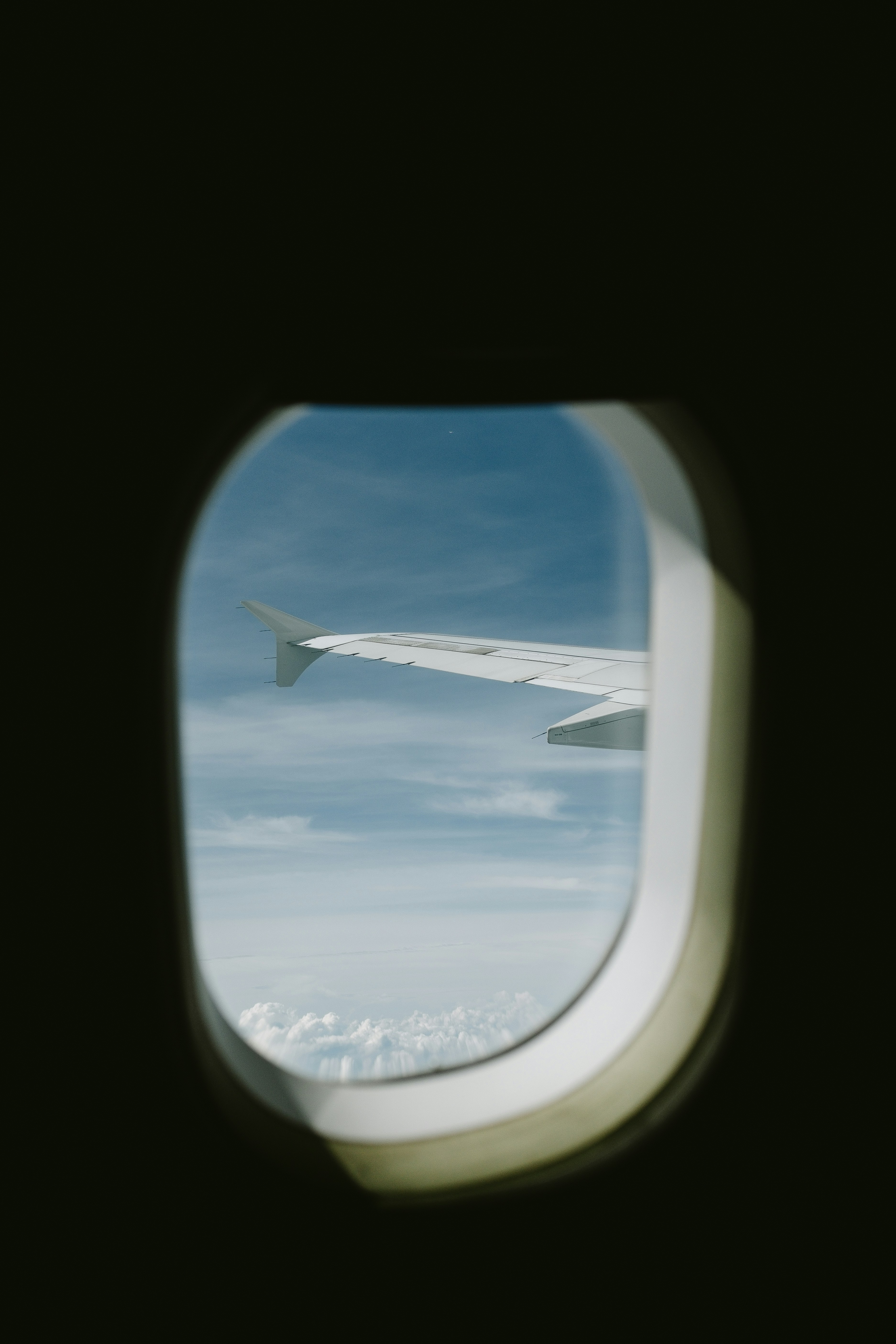 Airplane wing seen through a window above clouds