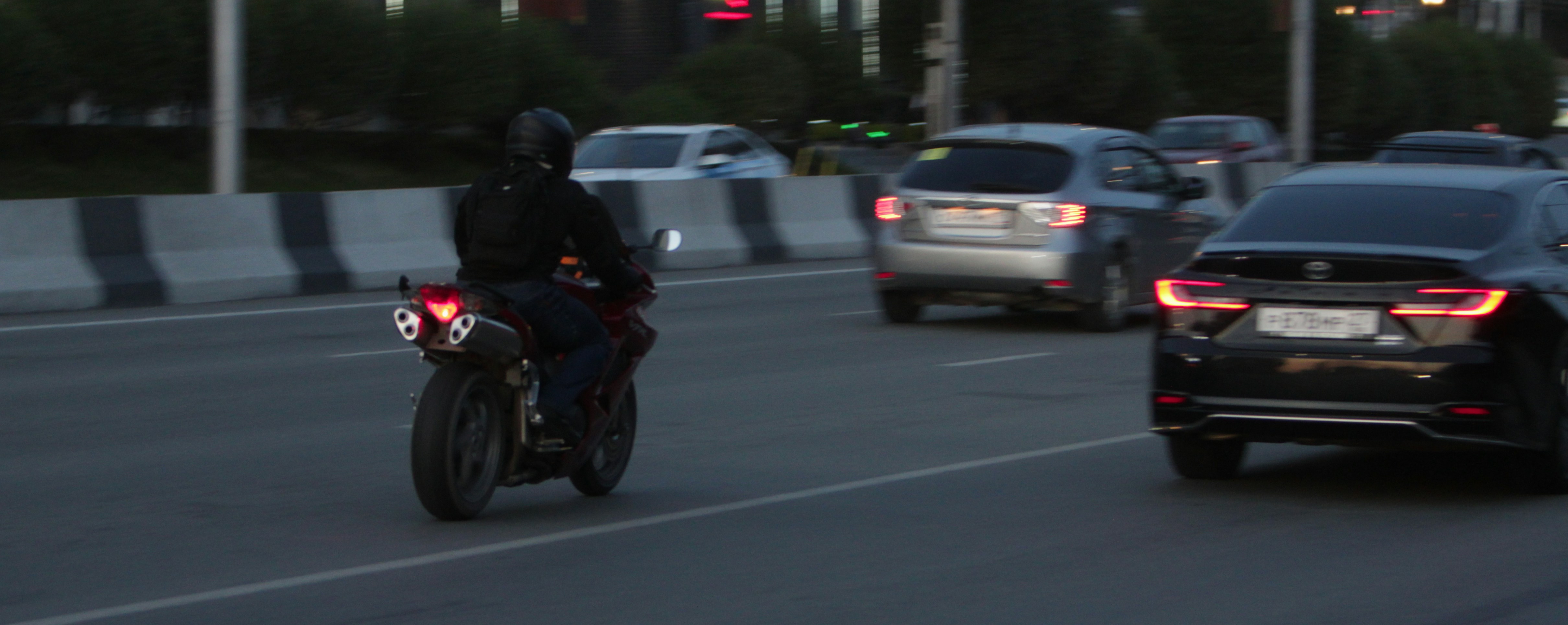 Motorcyclist riding on a highway with cars.