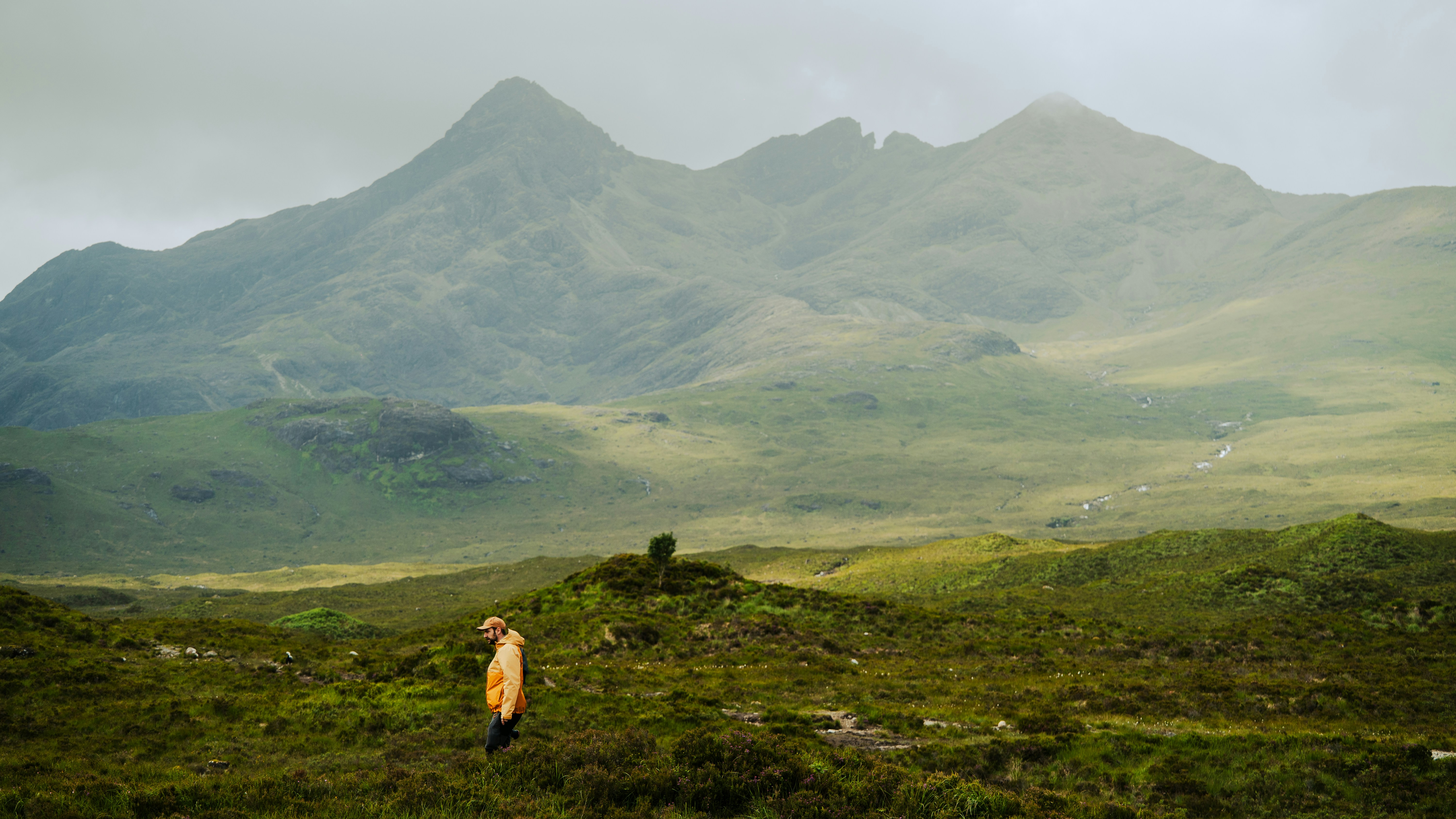 Lone Hiker on a Windswept Highland Moor Beneath Looming Peaks