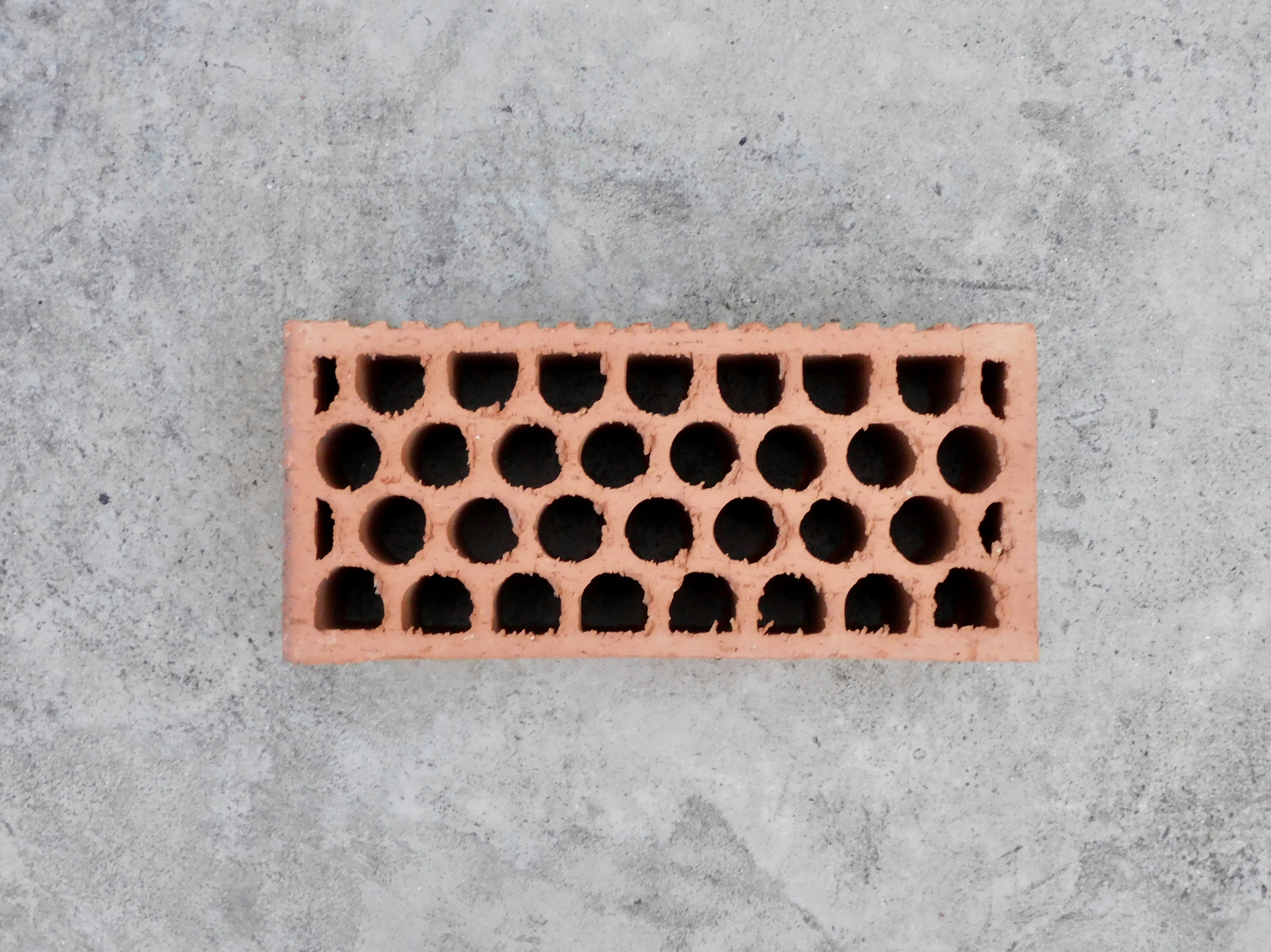Brick Lattice: A Single Brick Resting on Weathered Concrete