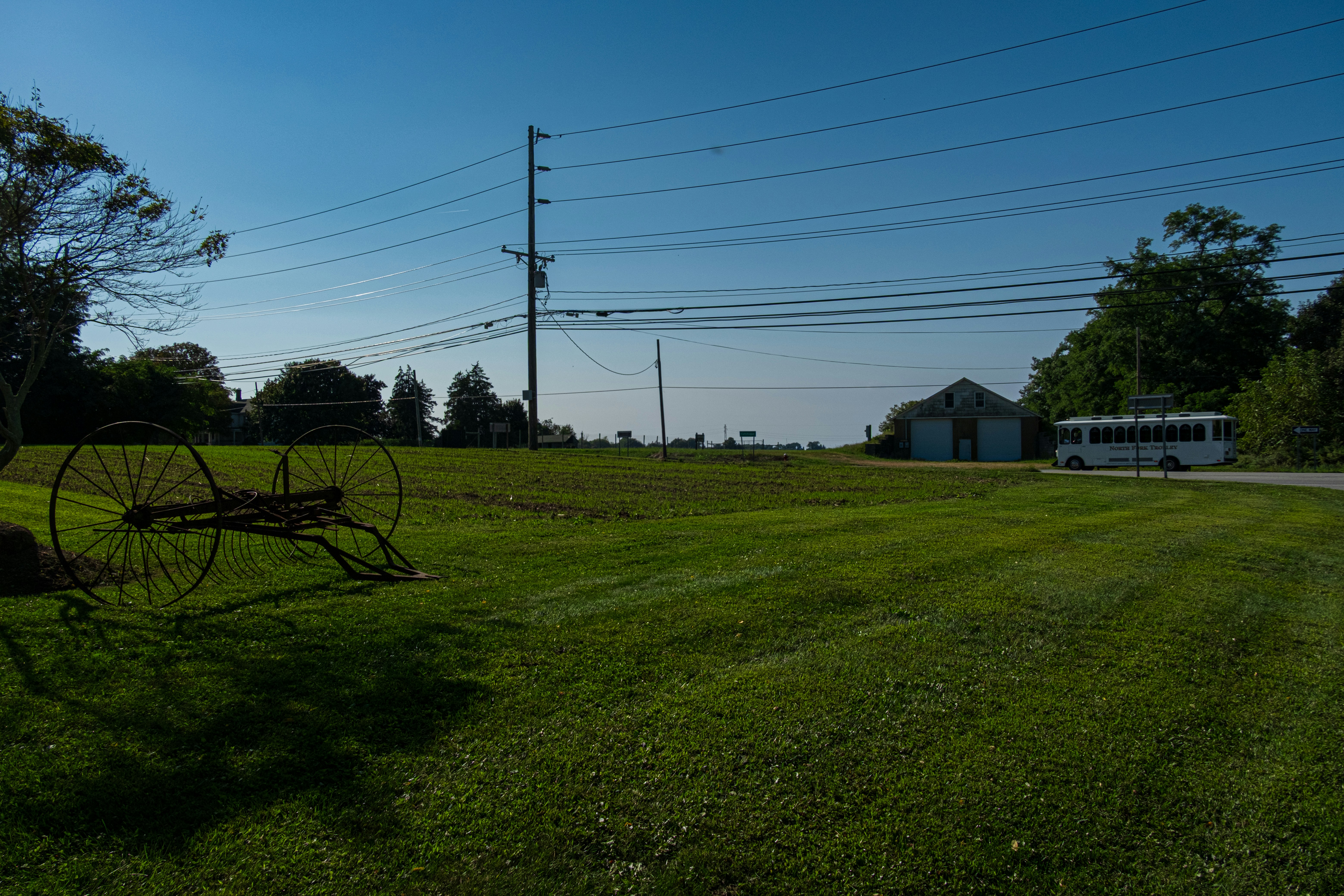 White bus drives past a barn and field.
