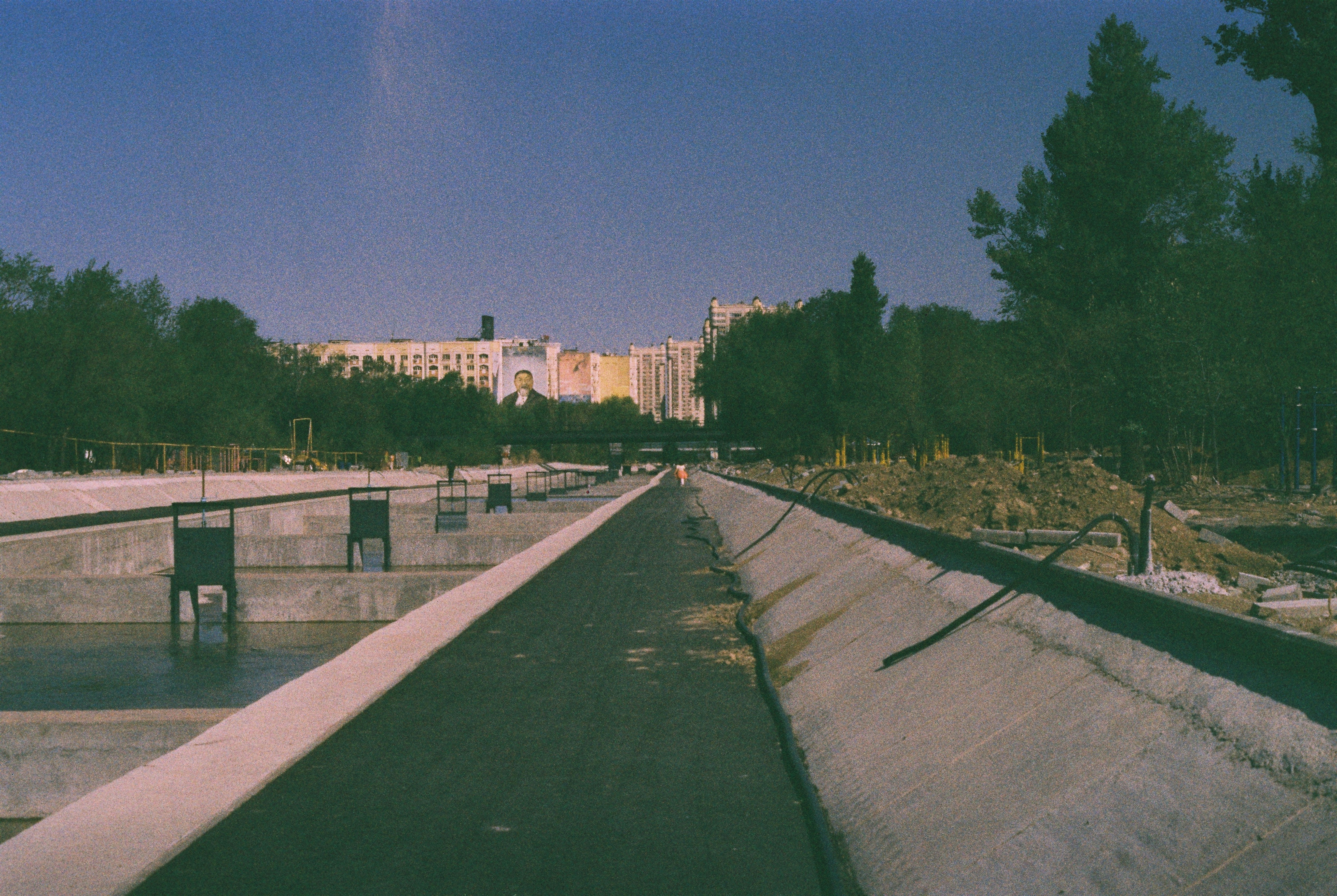 Concrete canal with trees and distant buildings