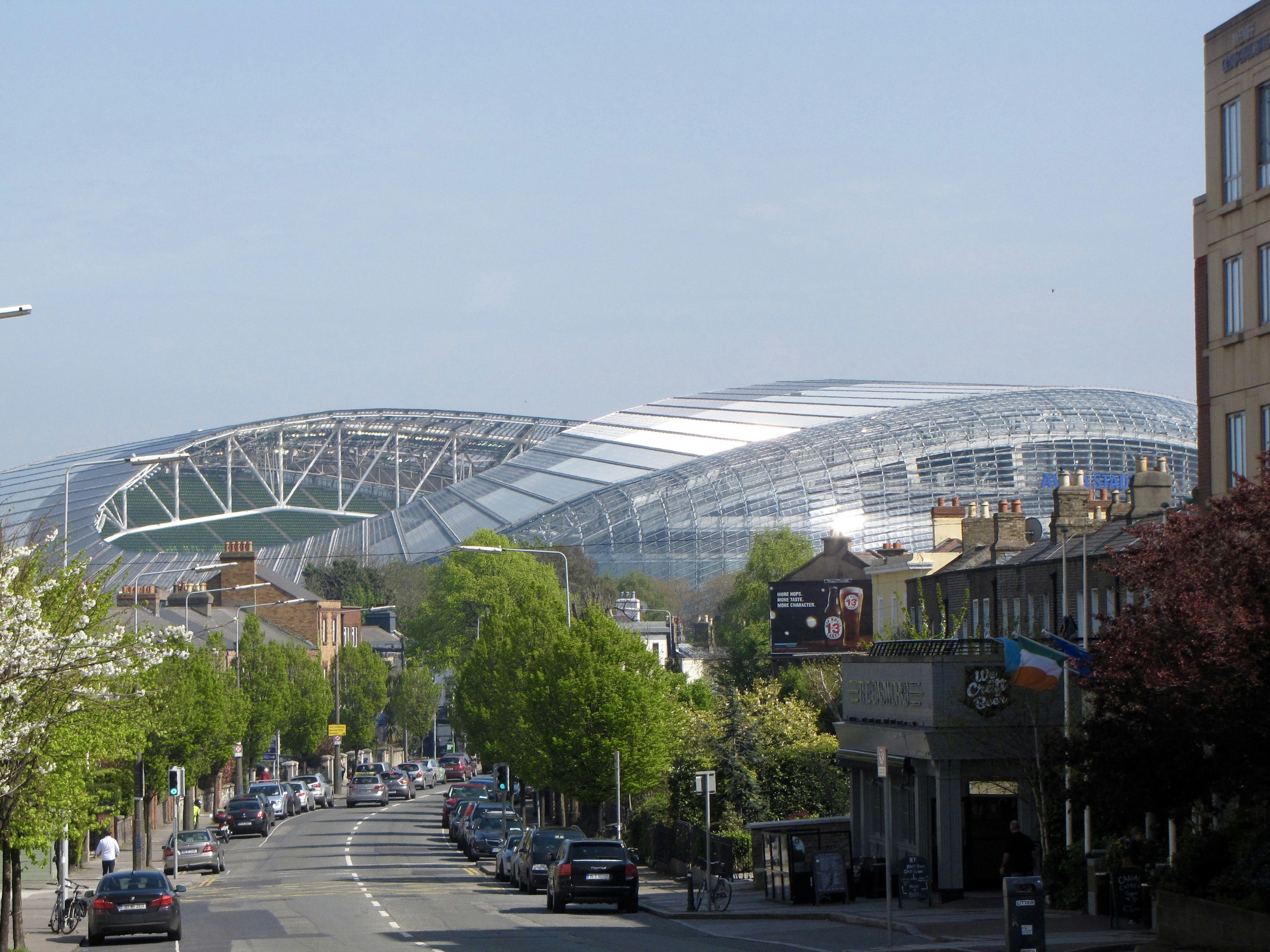 Modern stadium seen from a tree-lined street
