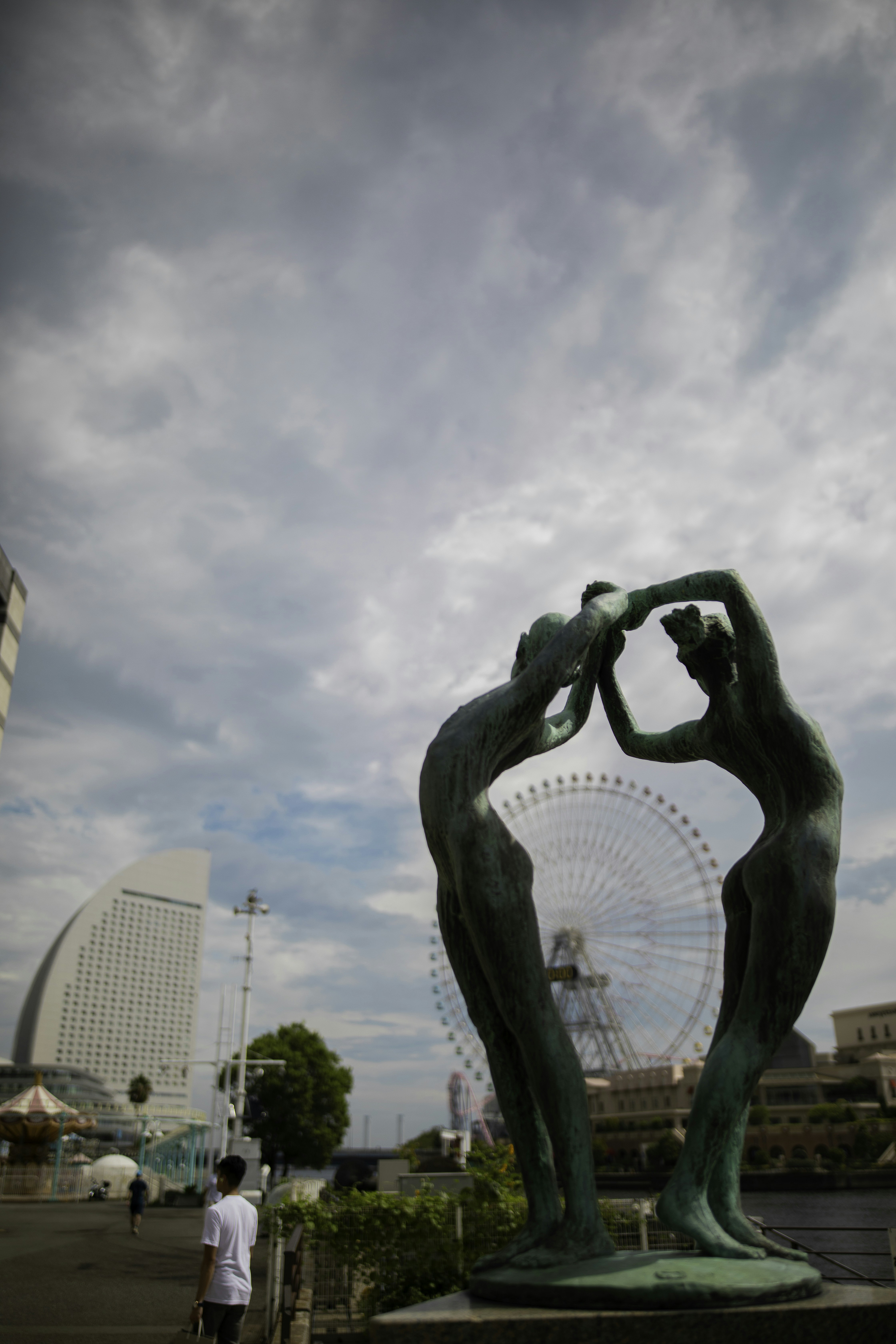 Sculpture of two figures with ferris wheel and building.