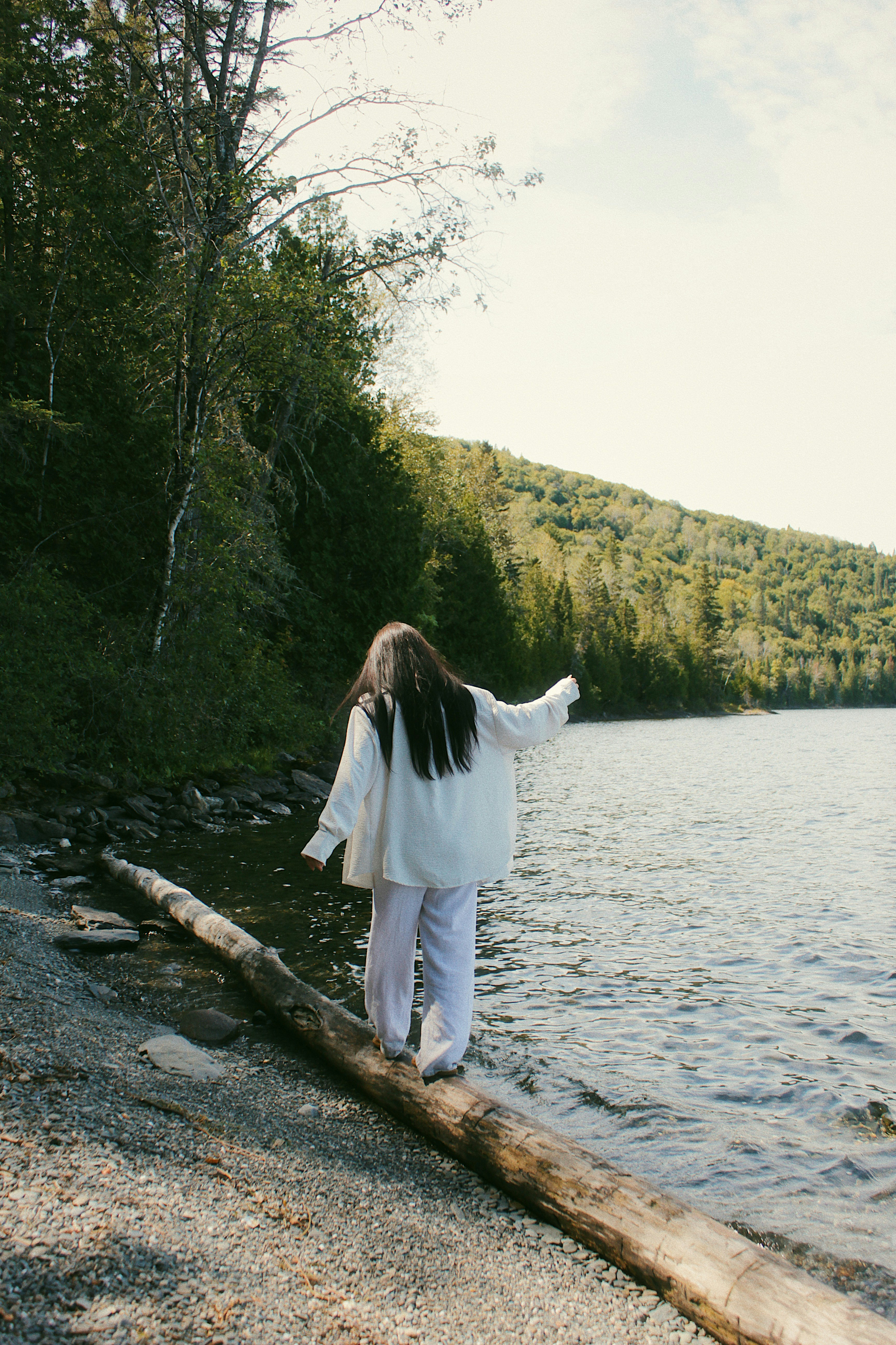Woman balancing on a log by a lake
