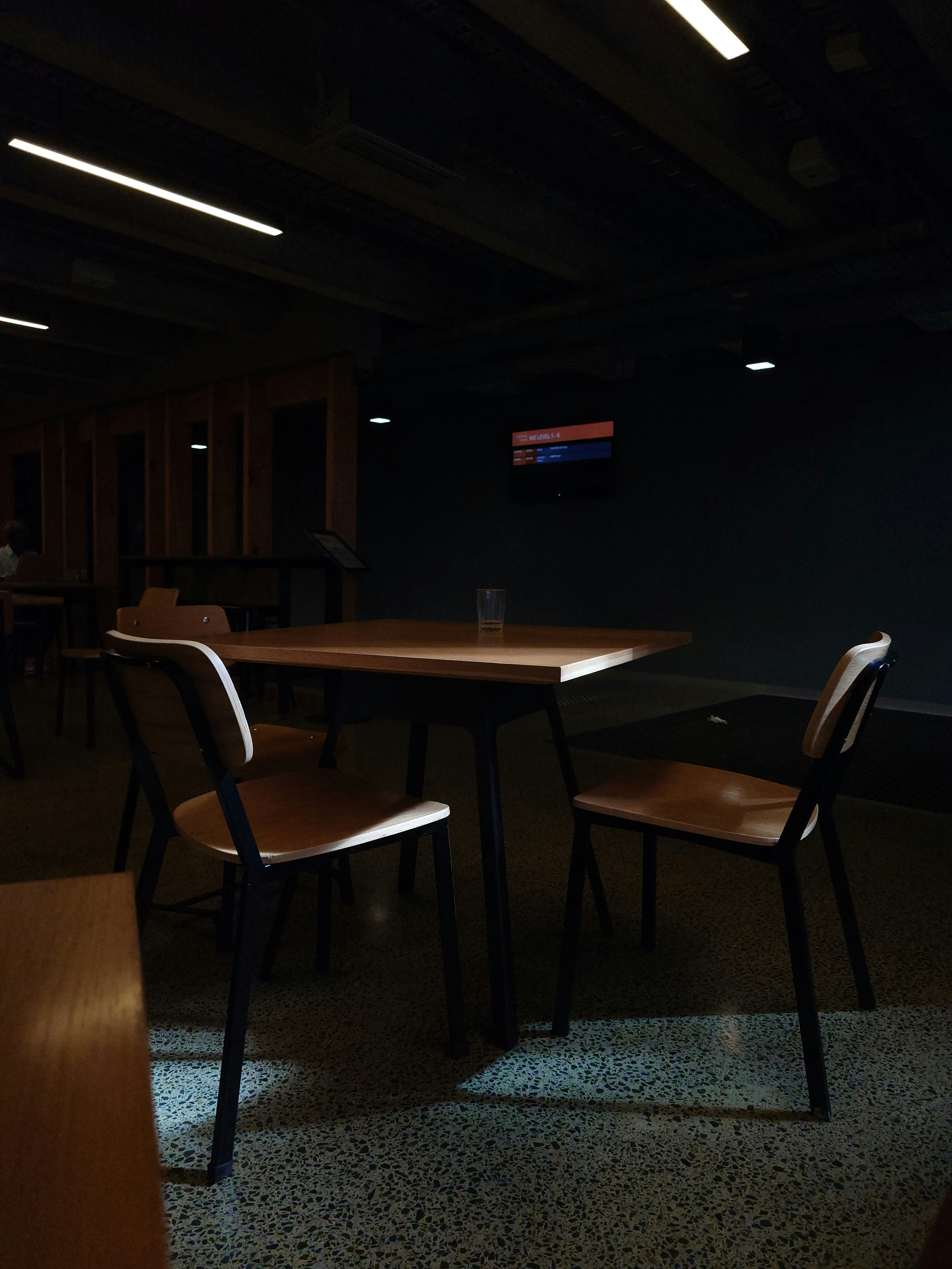 Two chairs at a wooden table in dim lighting.