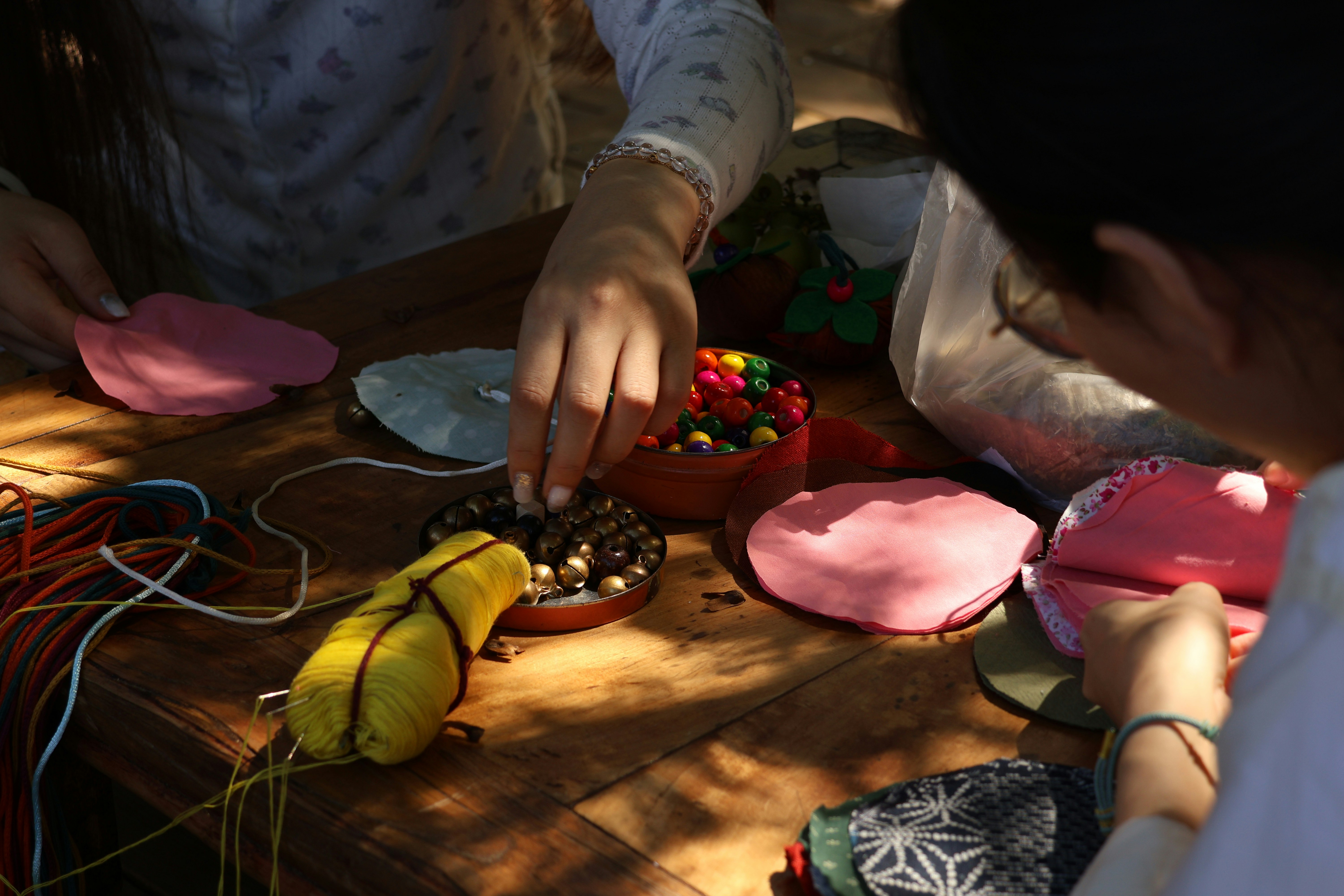 Traditional Ningbo handcraft making brings people together. | Hands crafting colorful objects on a wooden table.