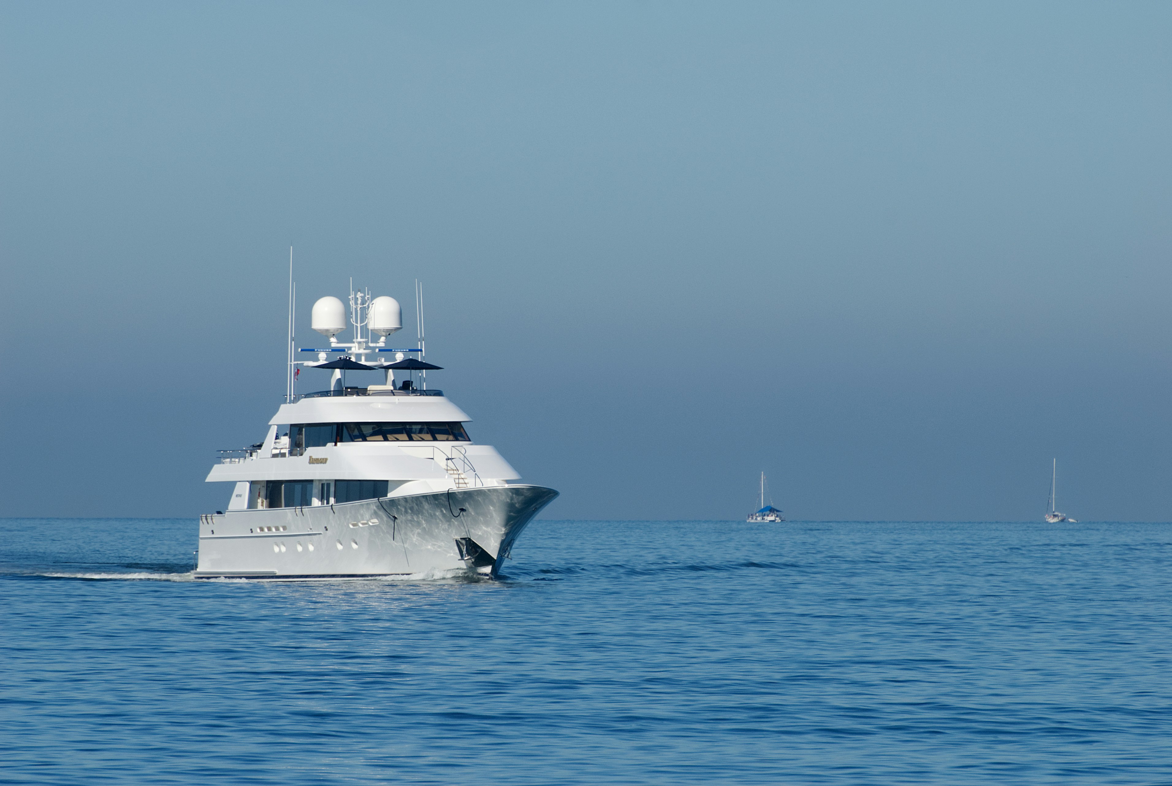 A yacht sailing in calm water | A white yacht cruises across a calm blue ocean.