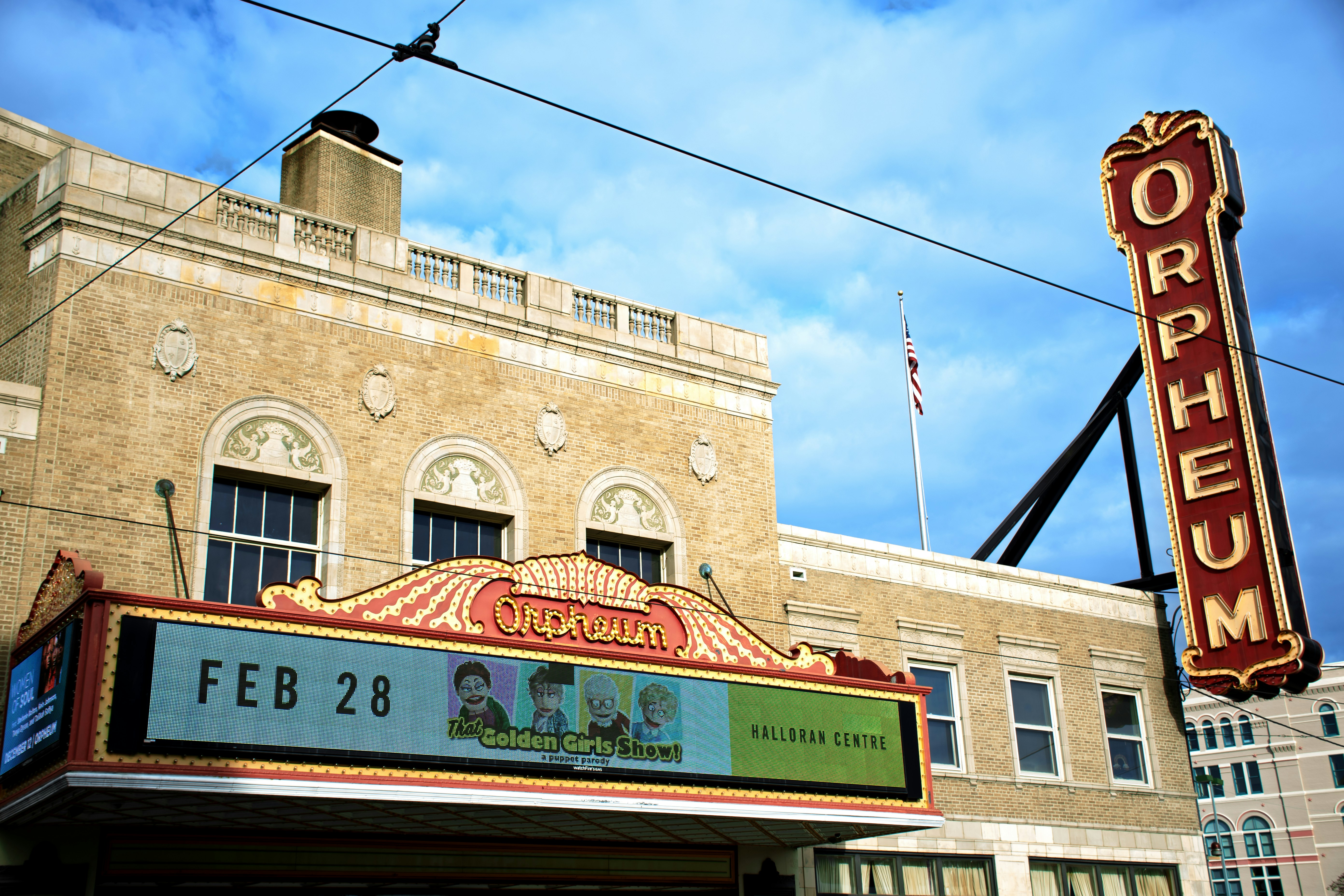 Historic Orpheum Theatre marquee showcasing an upcoming event, framed by classic architectural details and a vibrant sky.