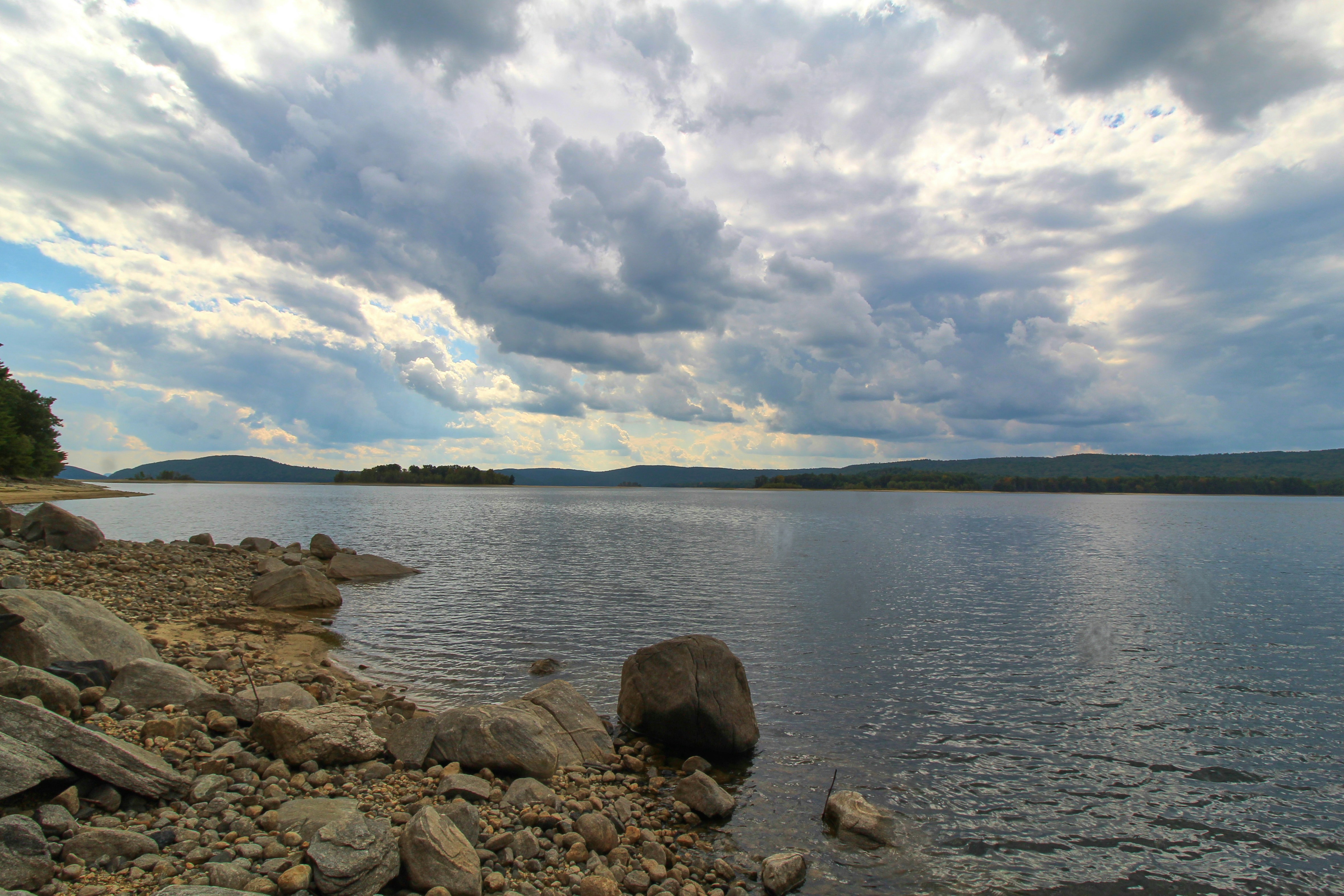 Calm lake with rocky shore under cloudy sky