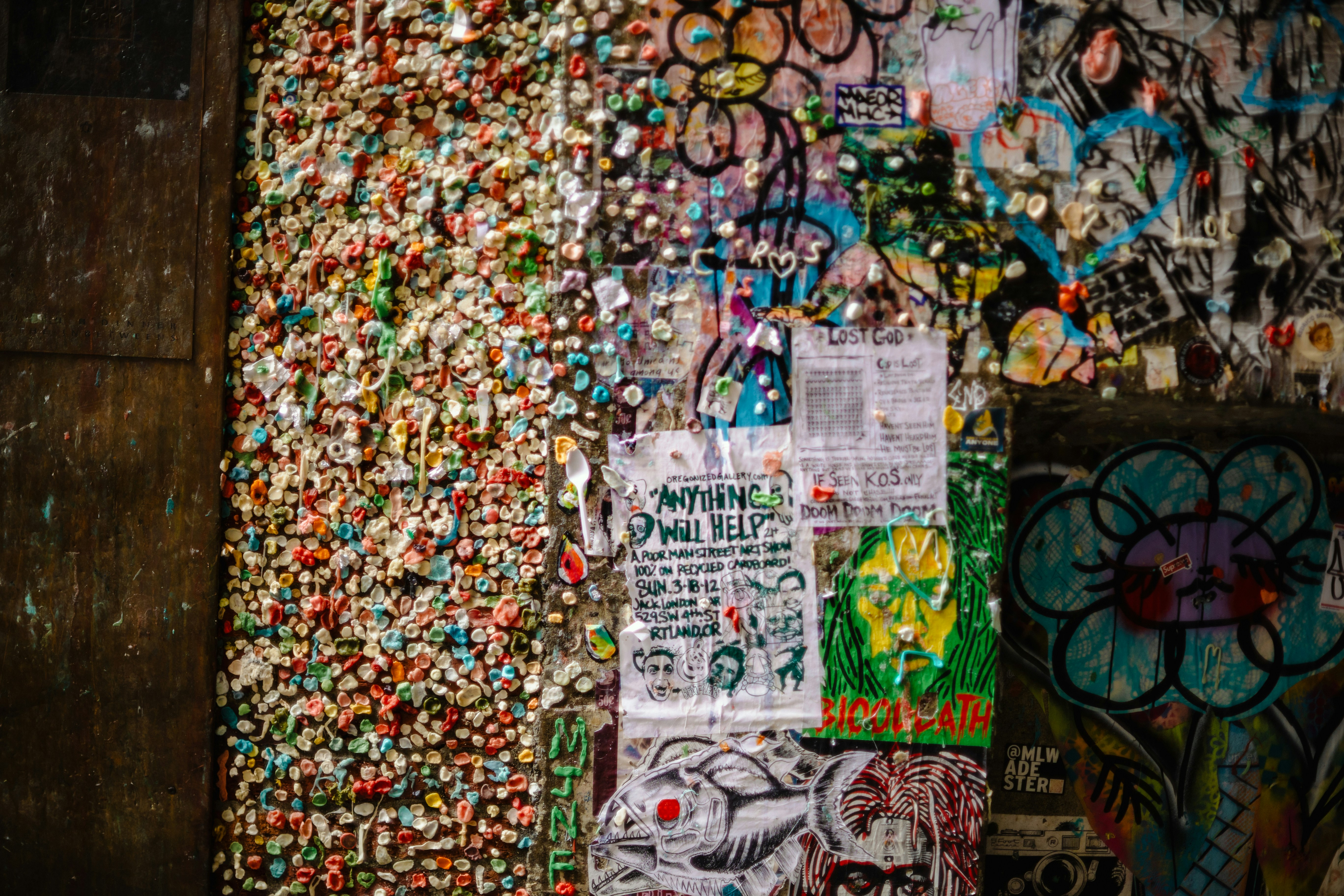 Green Portrait Anchors a Sticker Mosaic on an Urban Wall