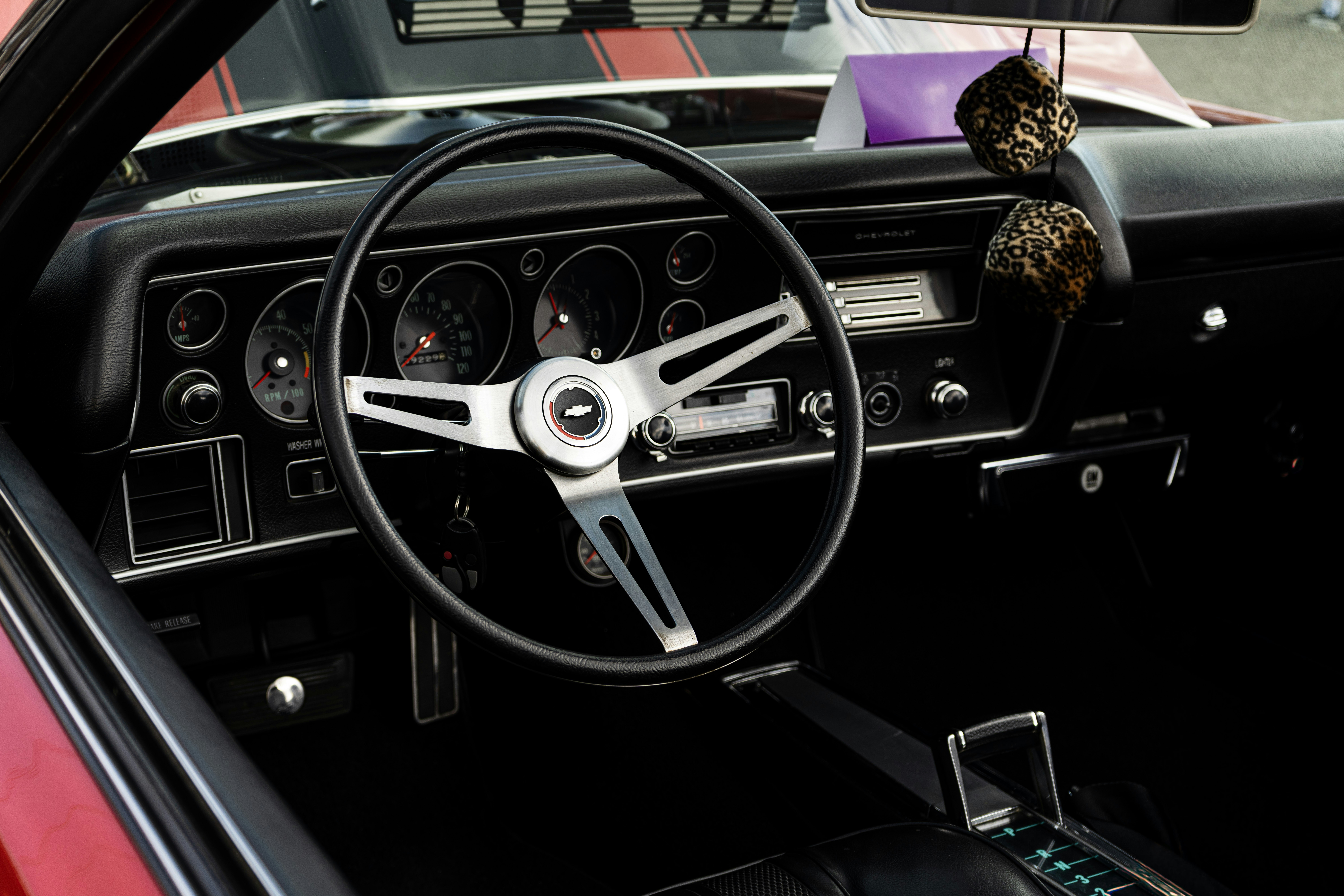Classic car interior showcasing a detailed dashboard with vintage gauges and a stylish steering wheel. The ambiance reflects a nostalgic automotive experience.