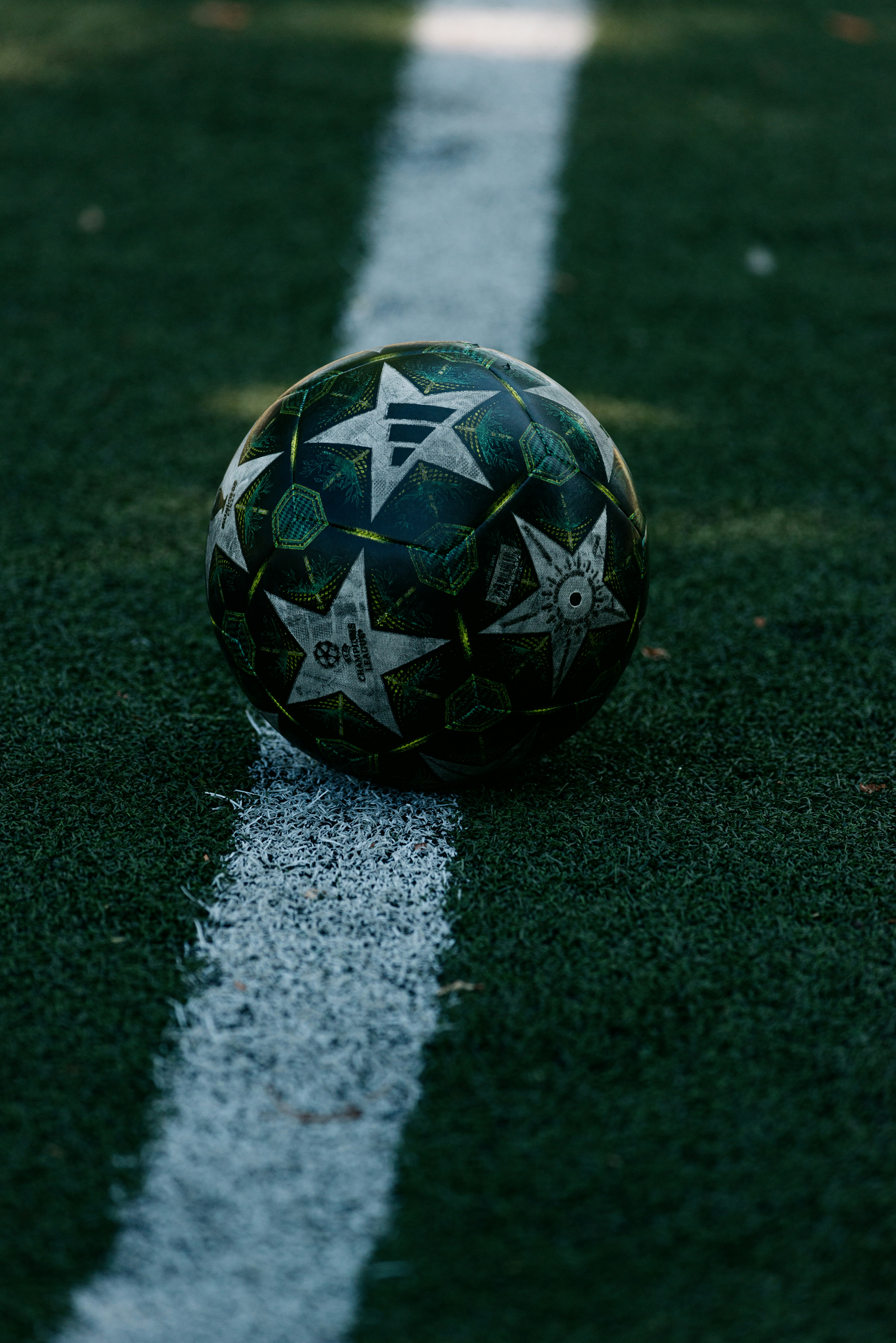 A soccer ball sitting on top of a soccer field. | Soccer ball with star pattern on field line