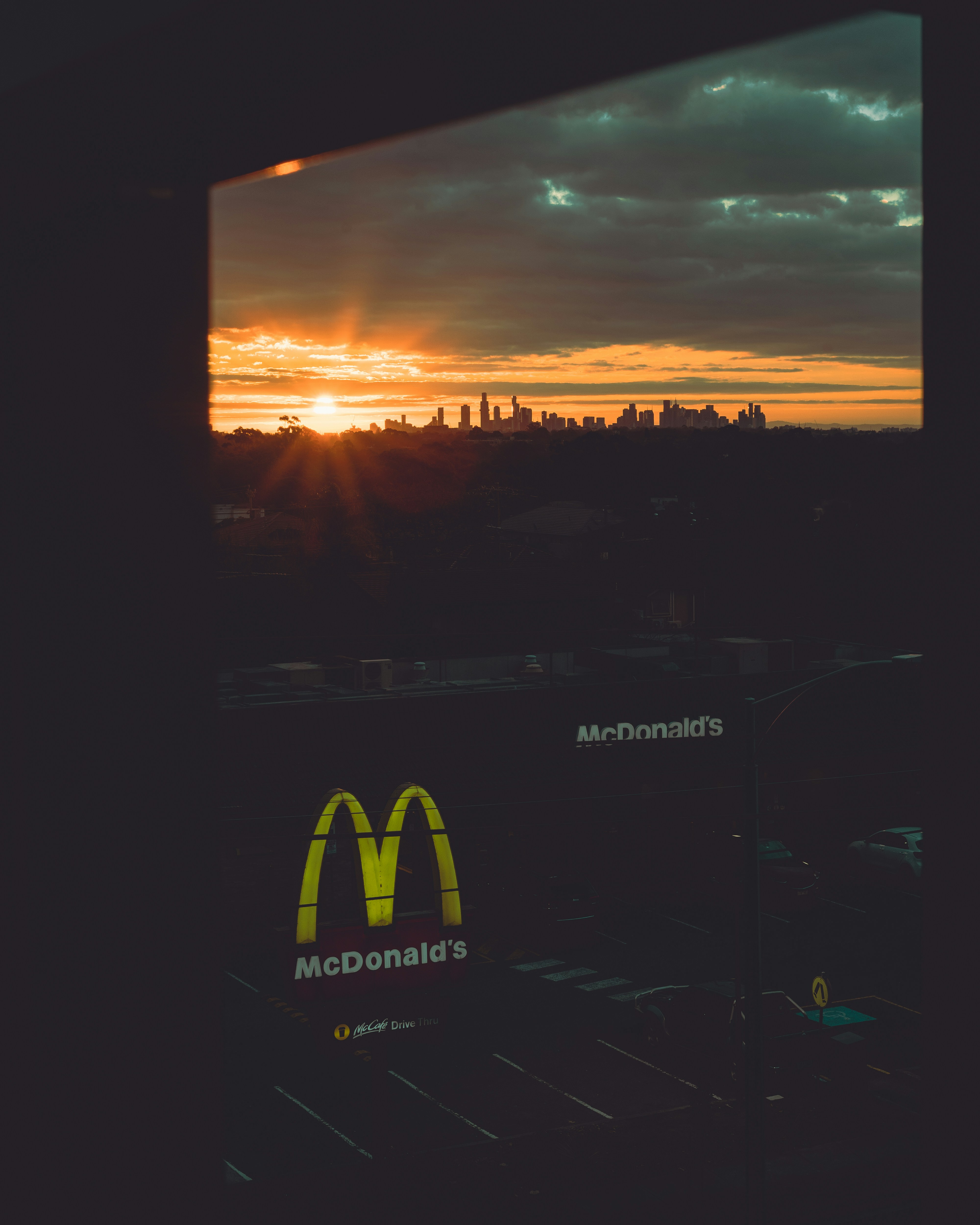 Sunset over city skyline with mcdonald's sign.