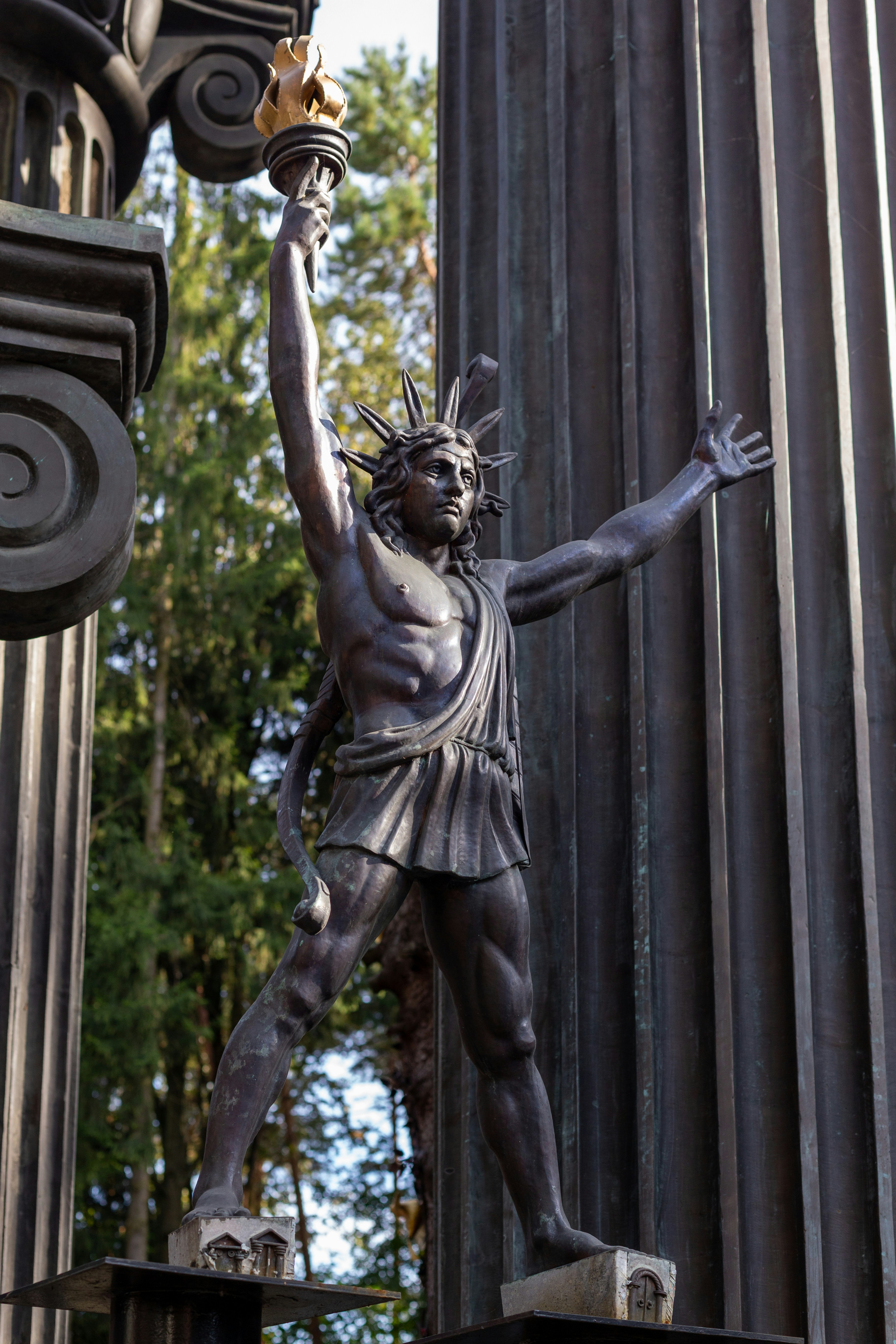 Bronze statue of a man holding a torch aloft.
