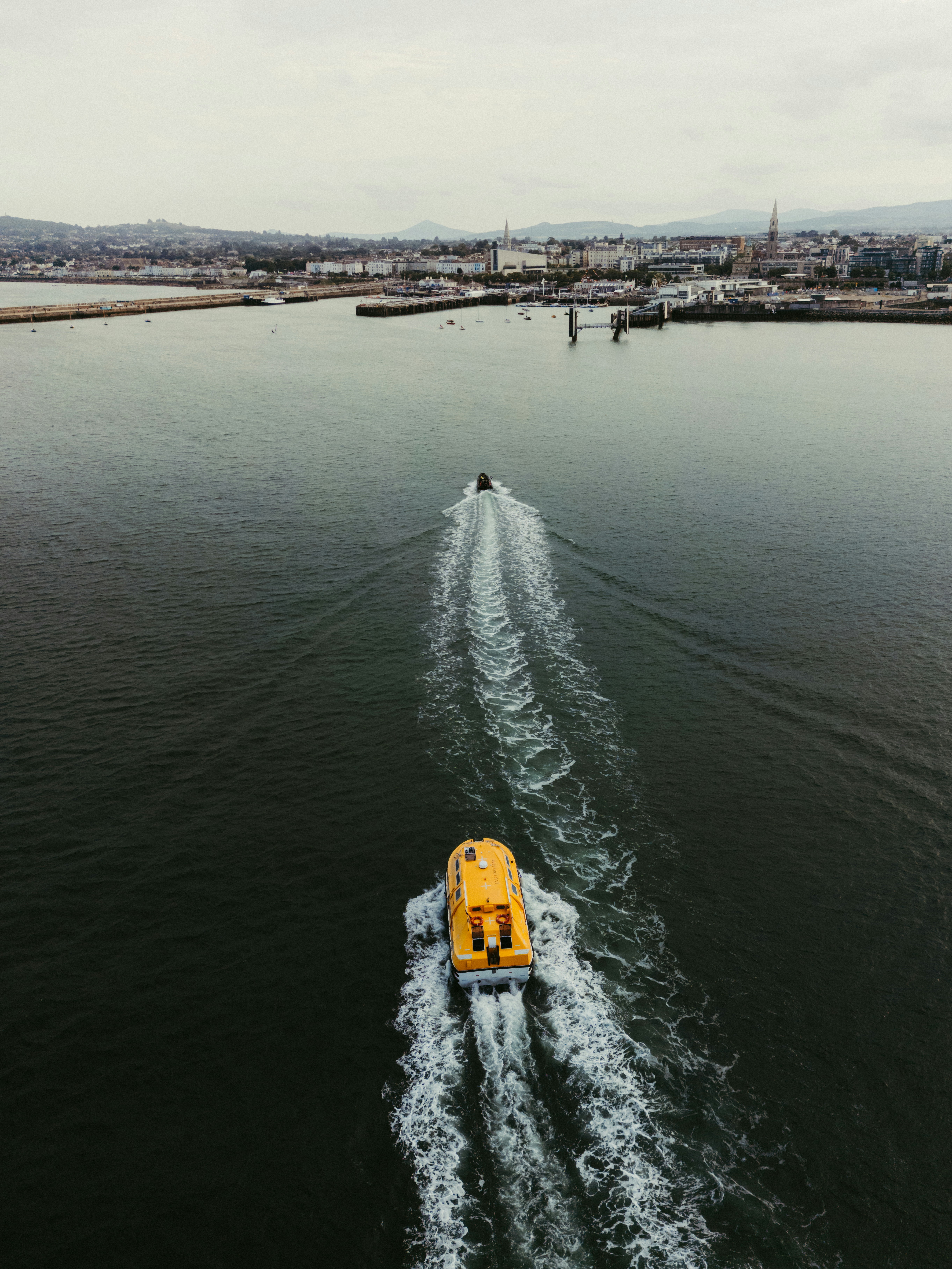 Yellow Vessel Cresting Through Harbor Wake: Aerial Reach Over Bordeaux-Like Waterfront