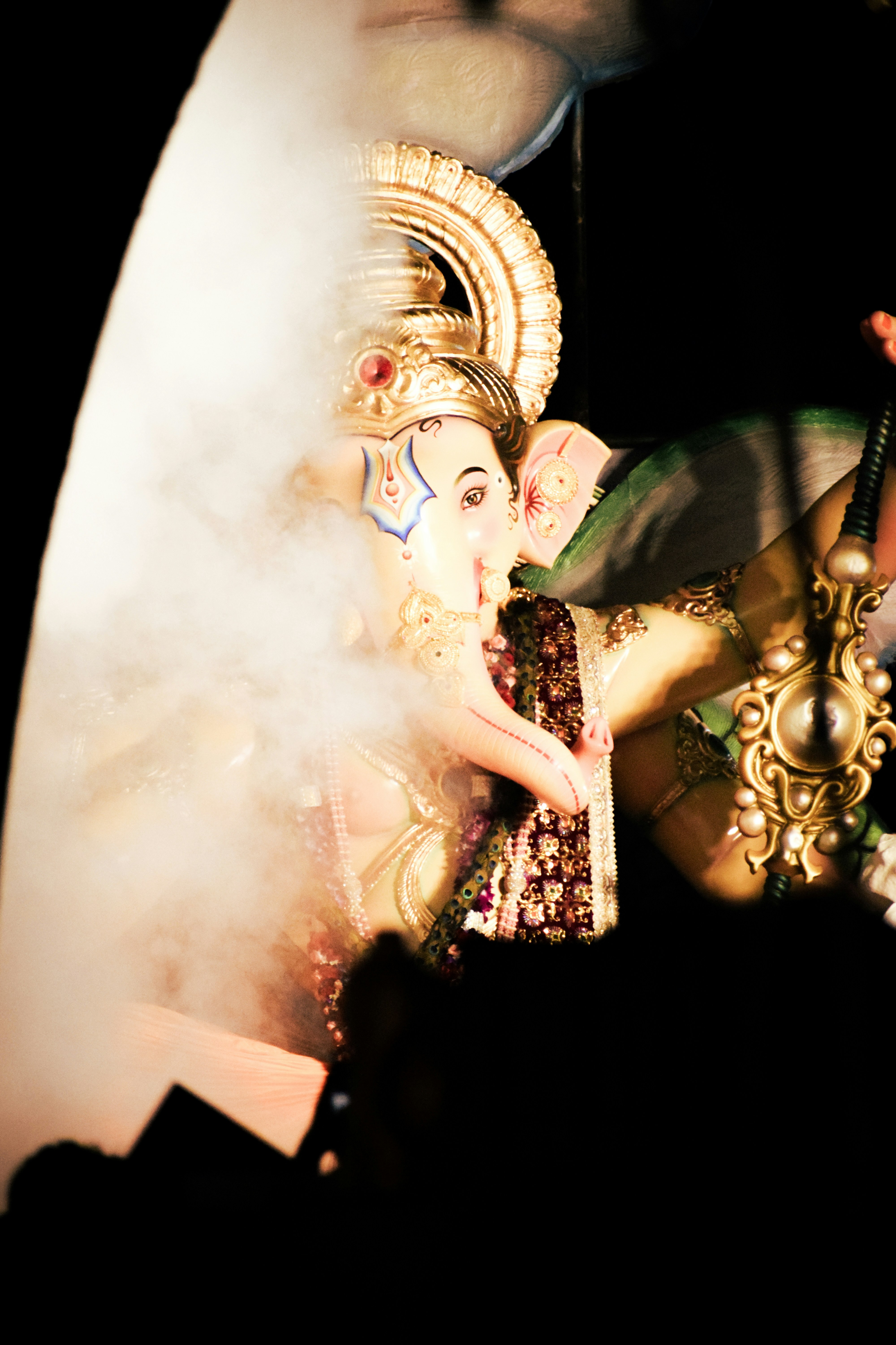 Smoke-veiled Ganesha: gold filigree and divine gaze in a festival moment