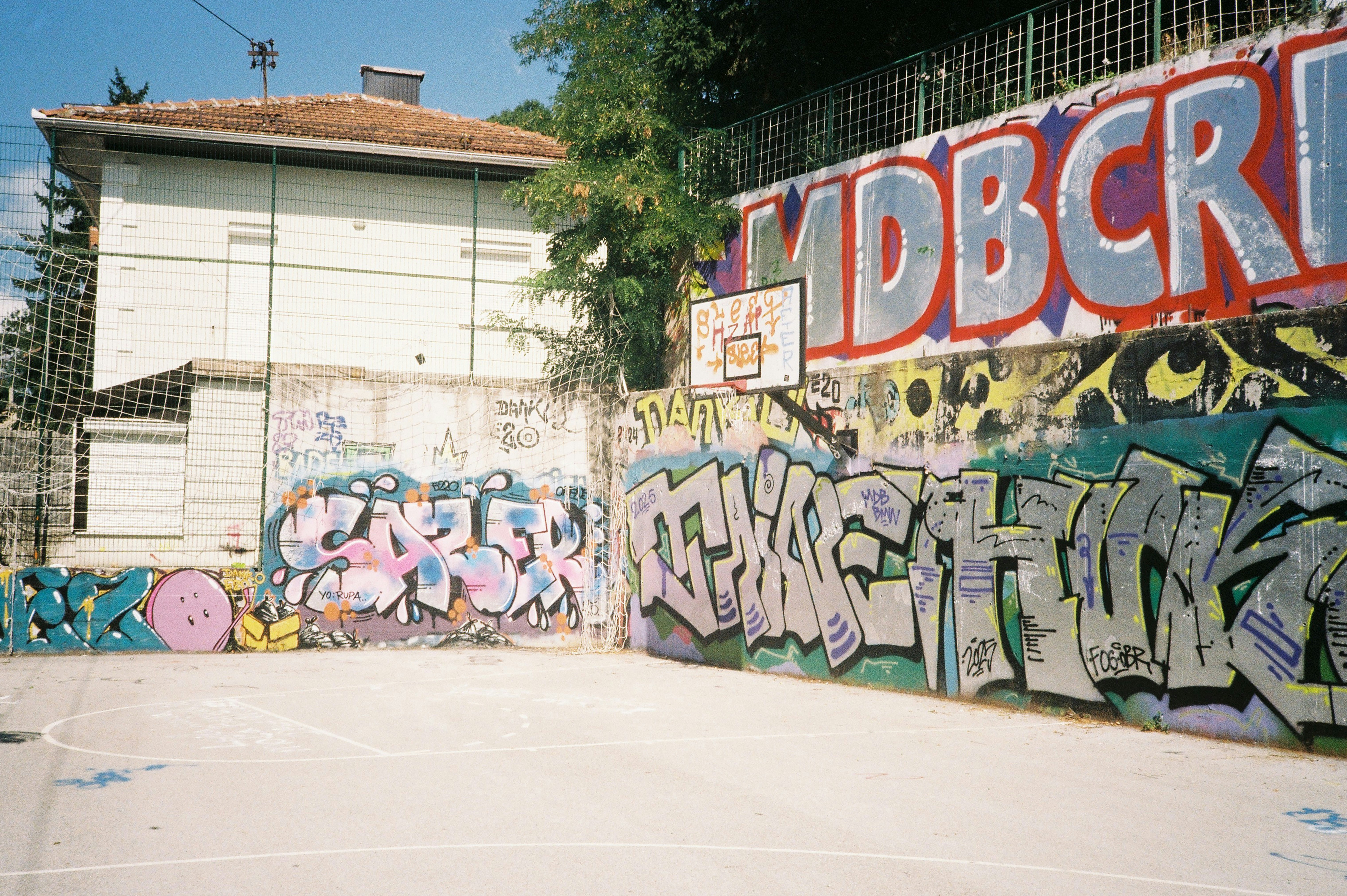 Attribution is appreciated (my Inst. @romi100gram) | Graffiti-covered walls surround an outdoor basketball court.