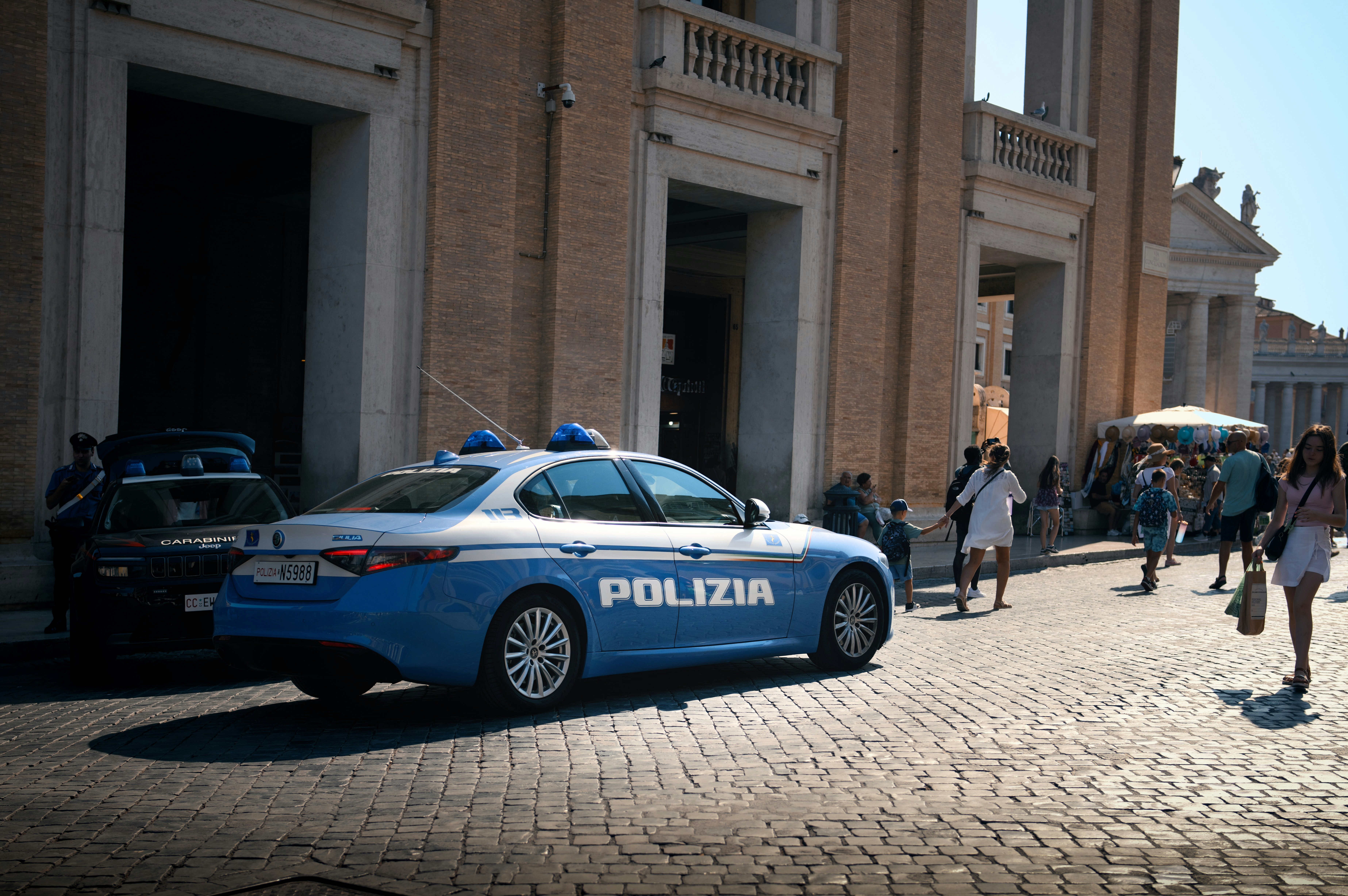 Police car parked outside building with people walking