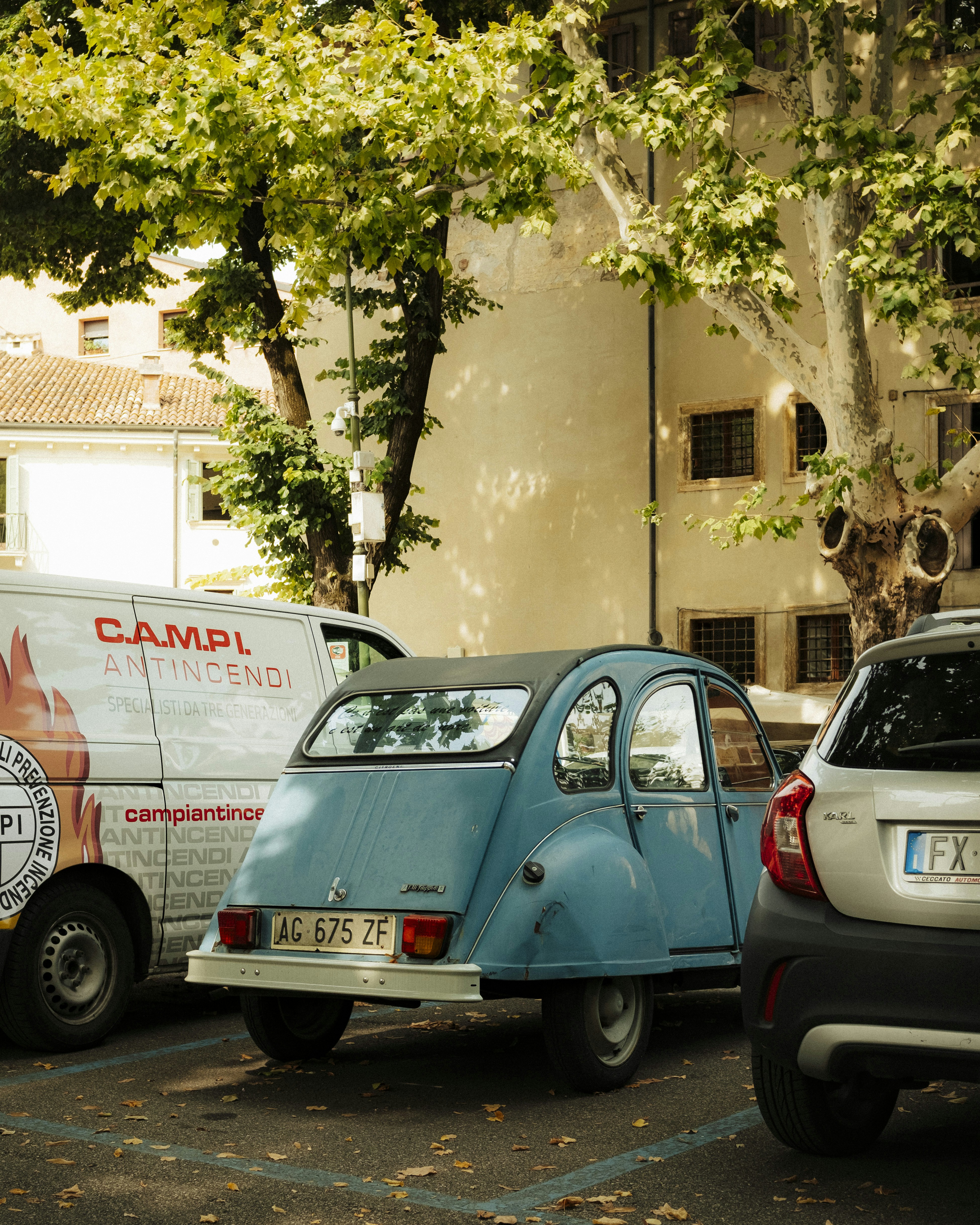 Blue Citroën 2CV in a Sun-Dappled Tree-Lined Street
