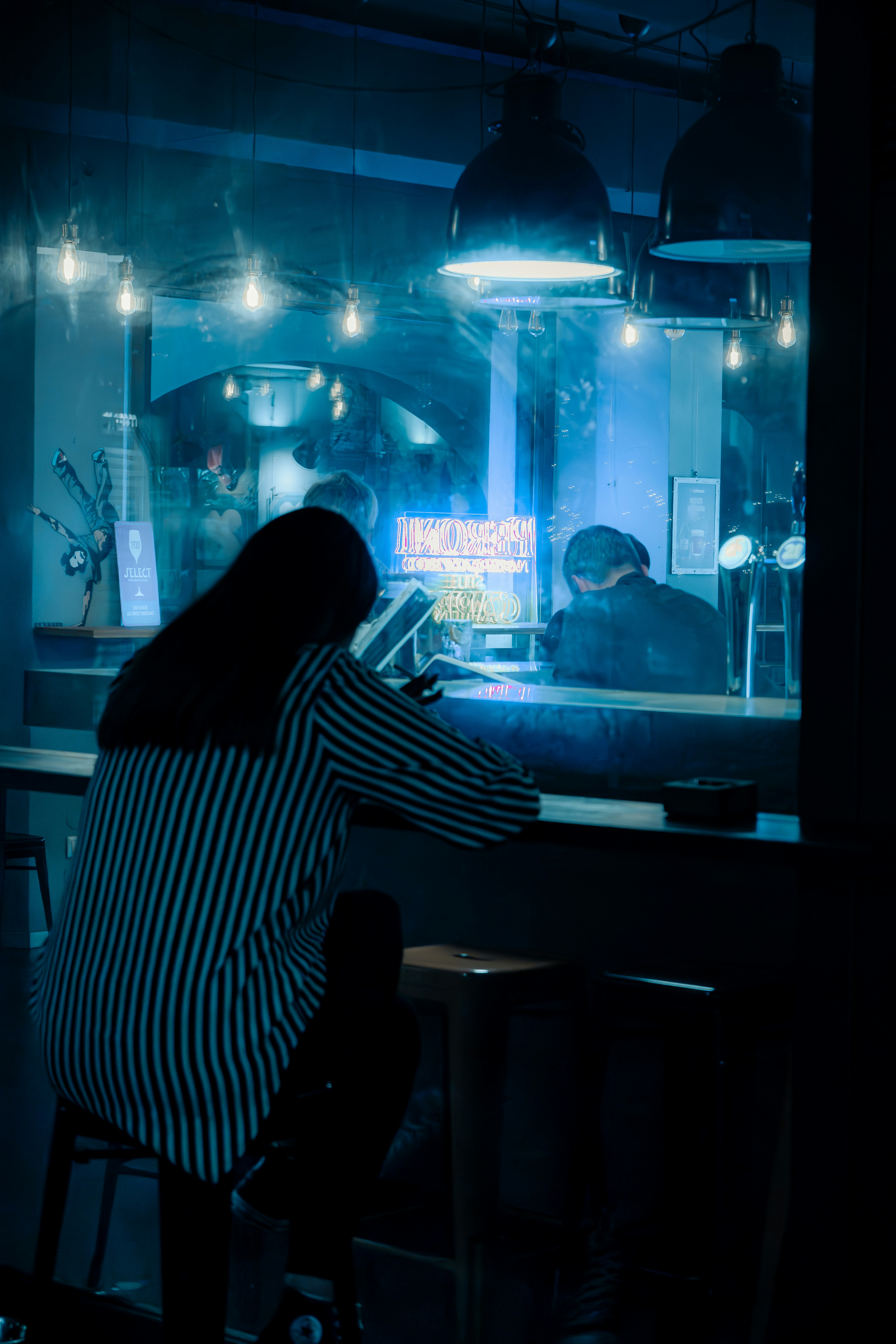 Blue Neon Through Glass: Striped Silhouette at a Neon-Lit Bar