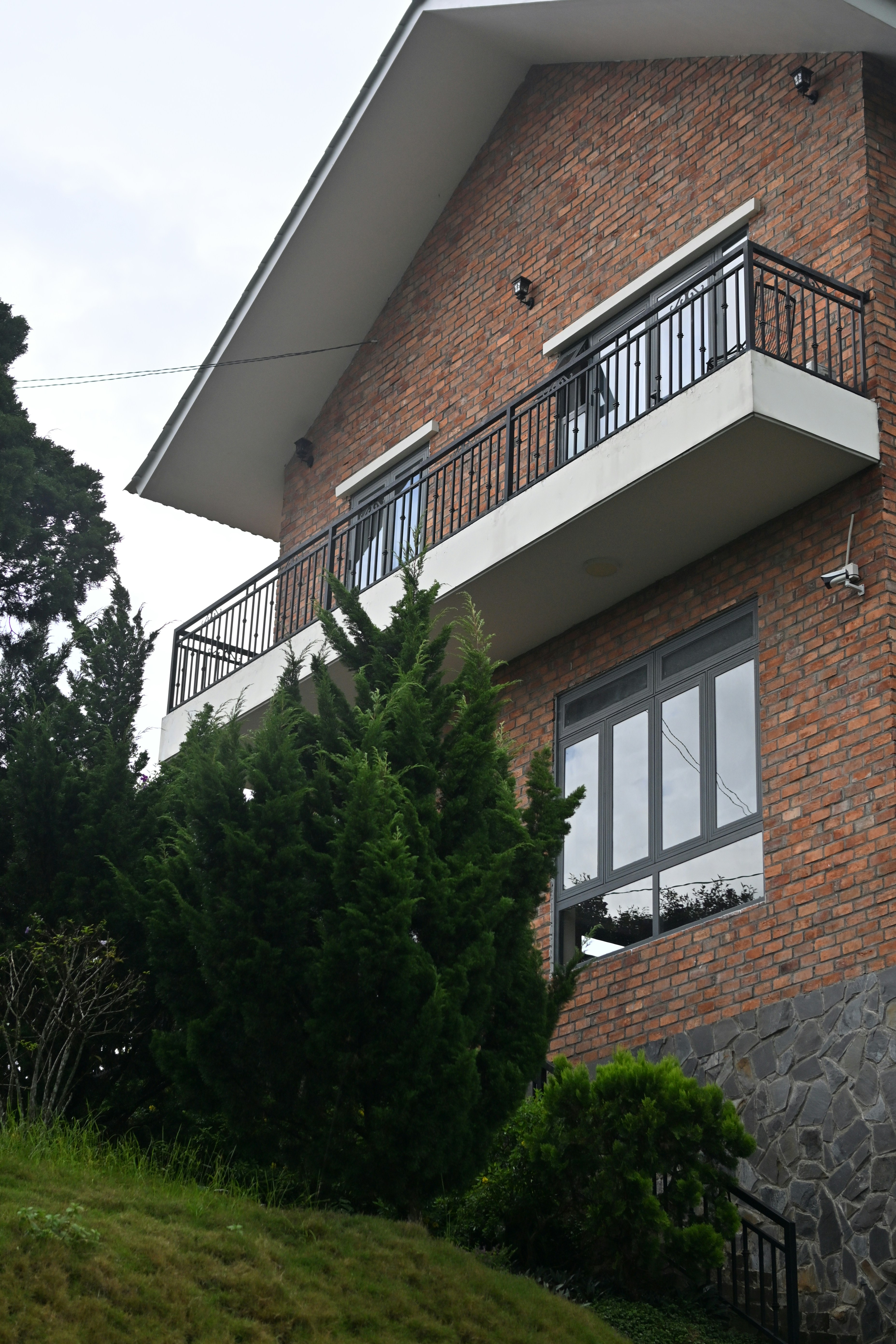 Brick building with balcony and large windows.