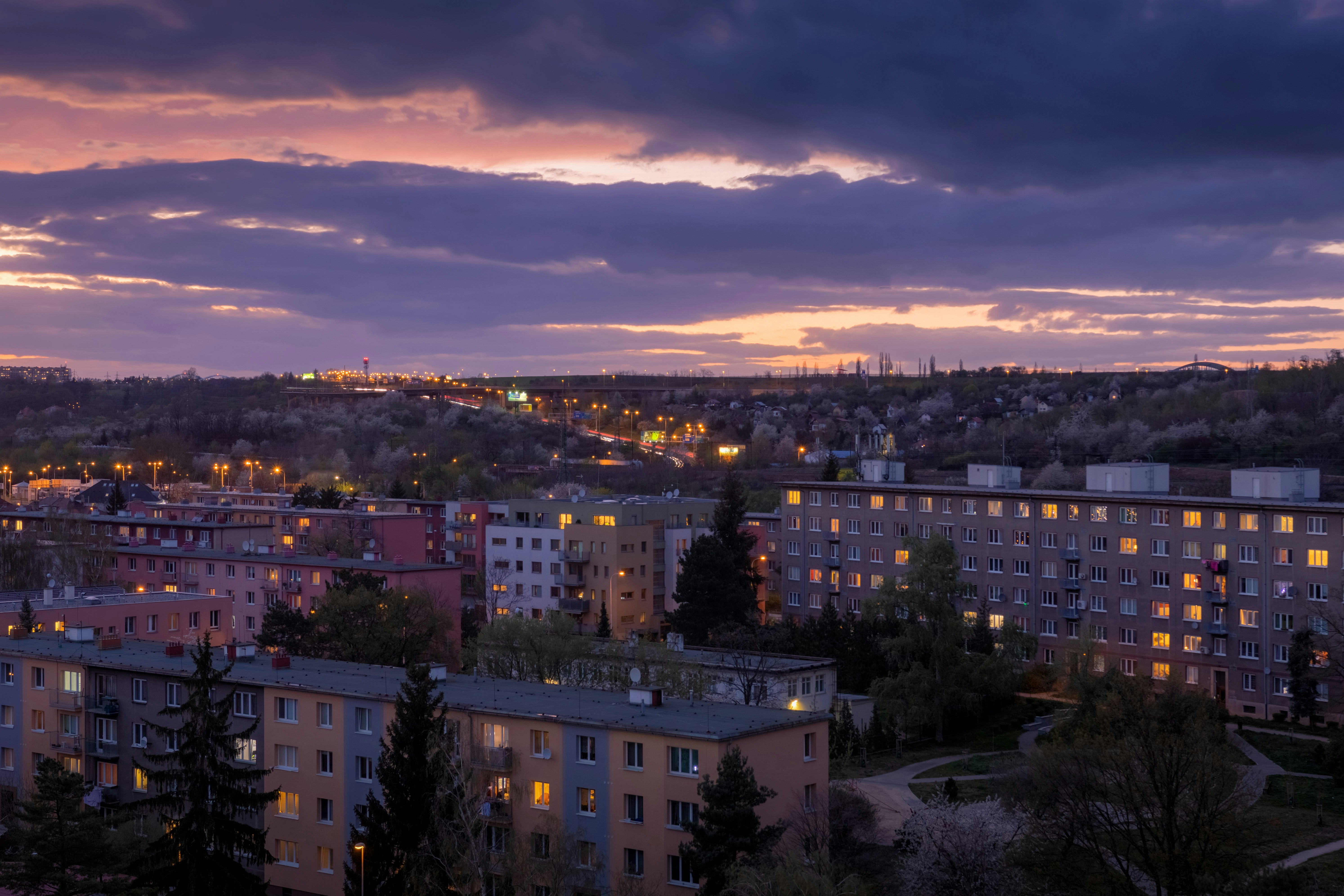 Cityscape at twilight with colorful clouds and lit windows.