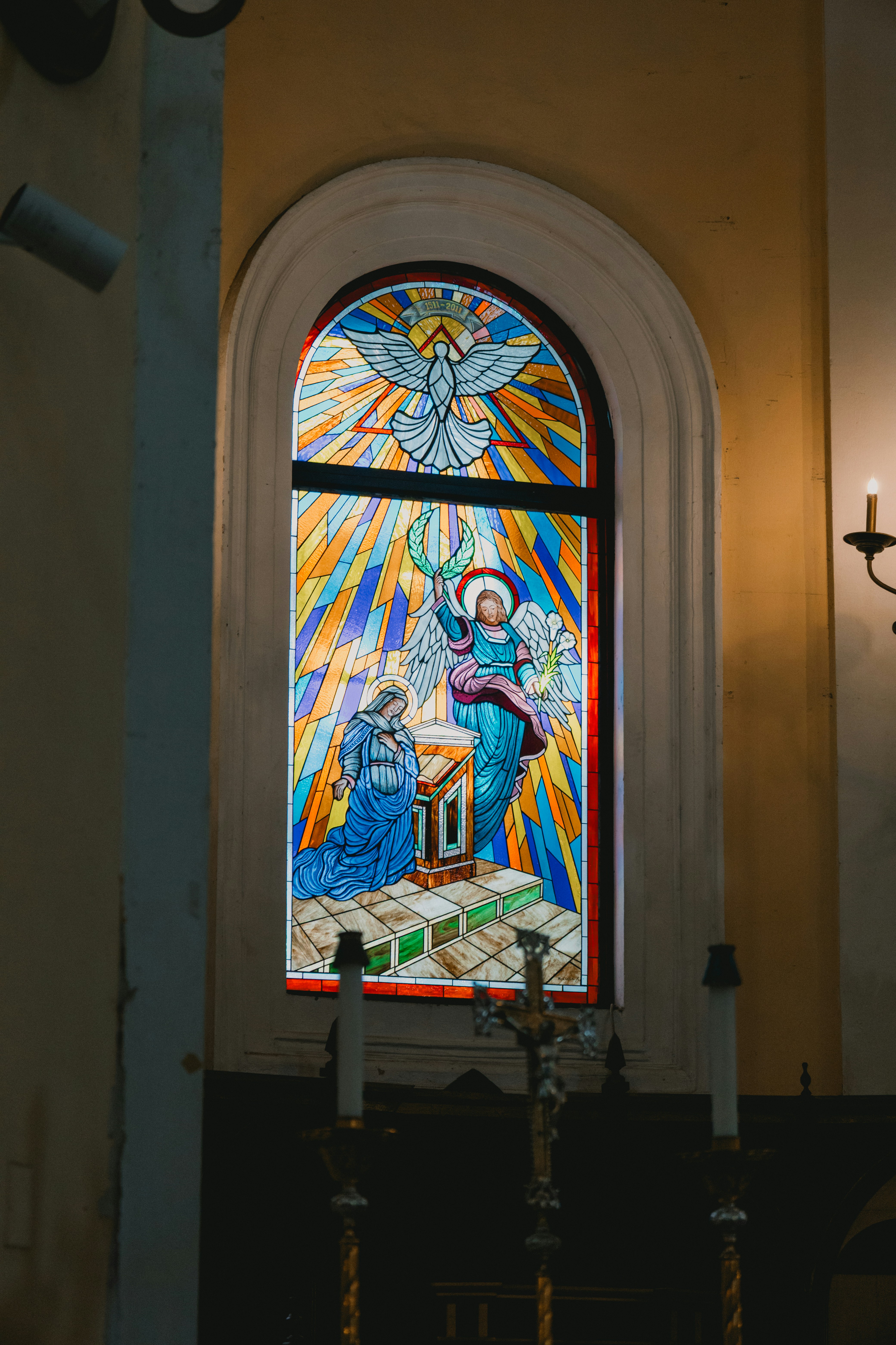 Stained glass window depicting religious scene with angel and dove.