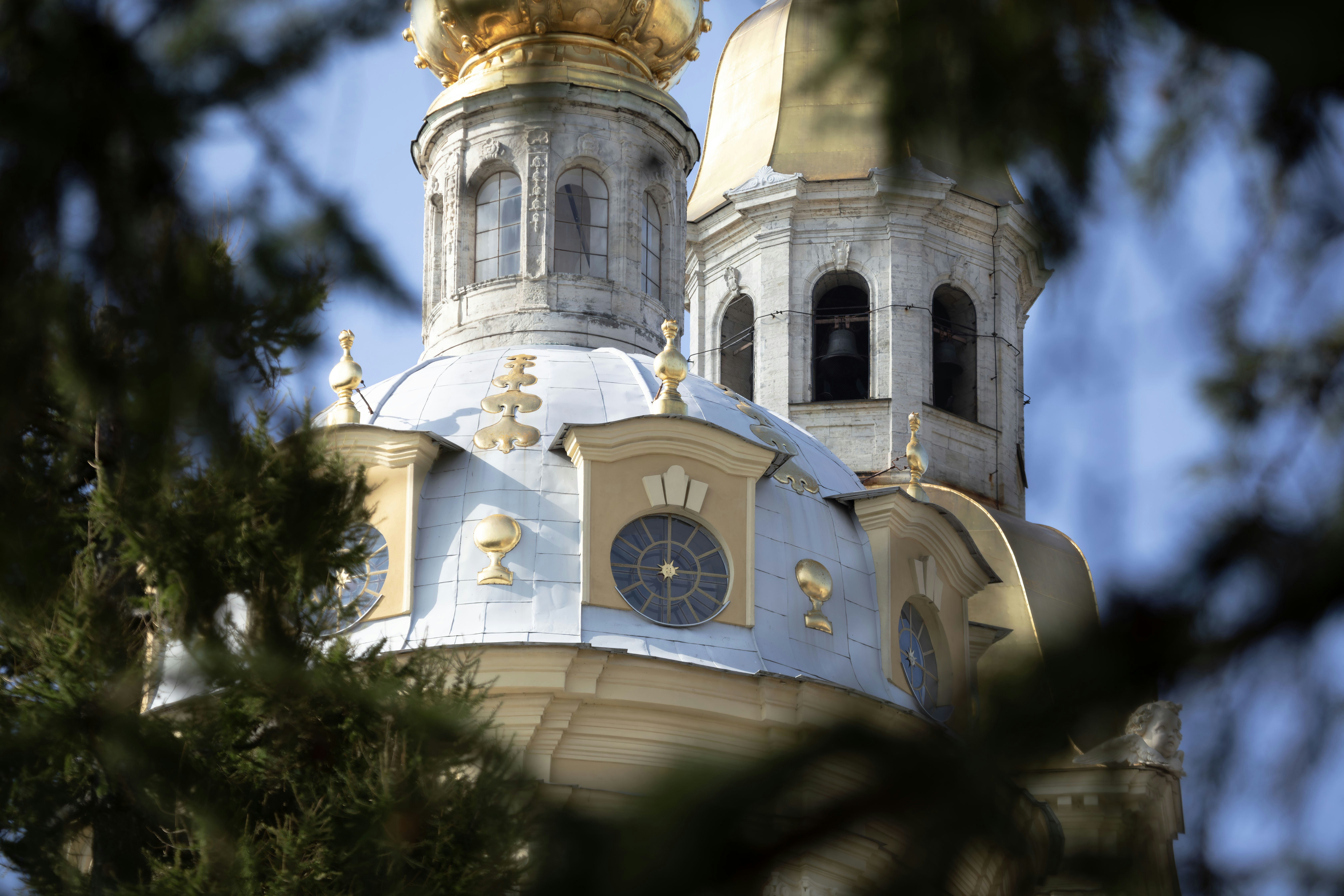 Peter and Paul Fortress, St. Petersburg | Golden domes of a historic cathedral seen through trees.