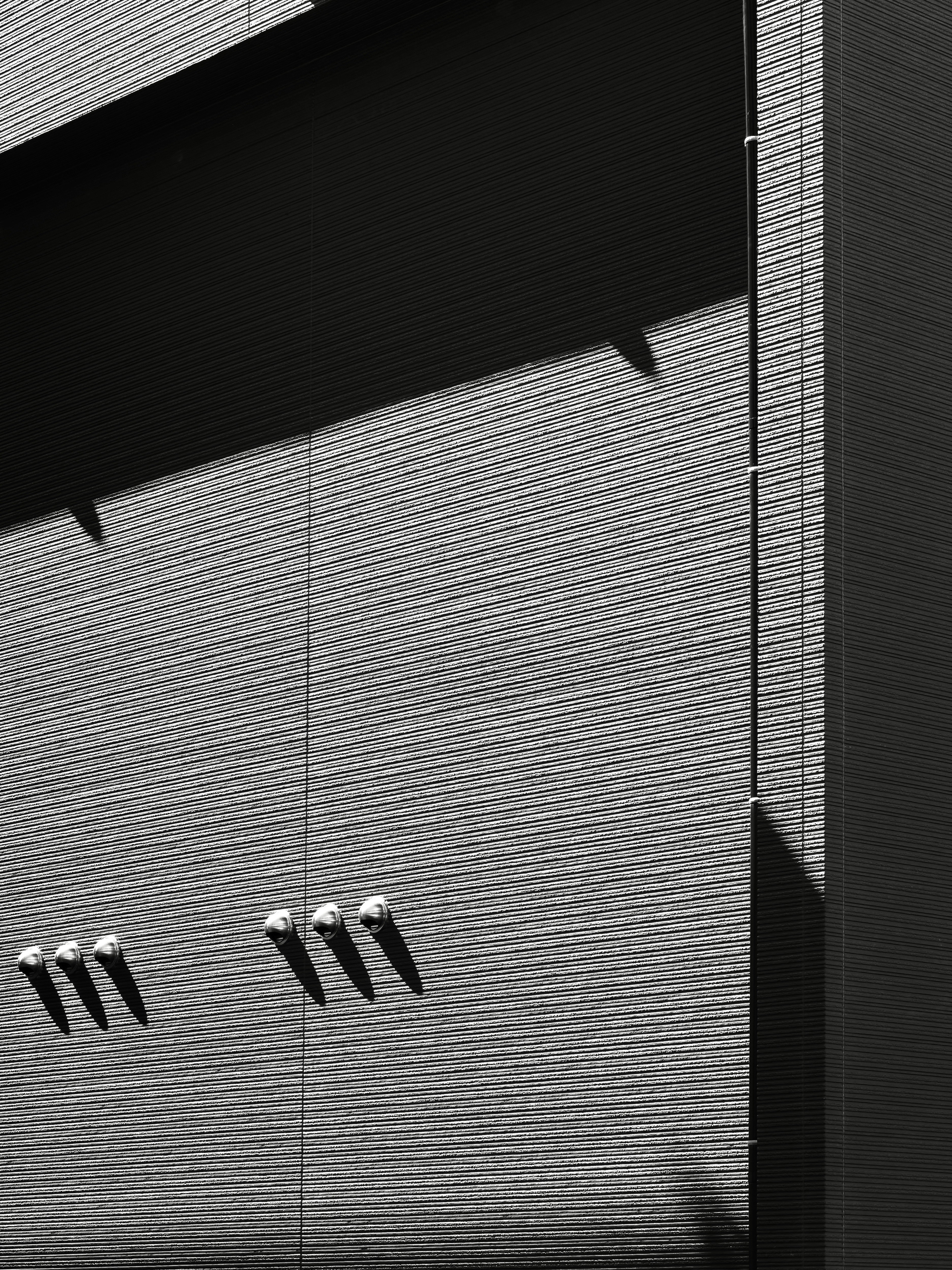 A textured facade | Shadows cast on a textured brick building wall.