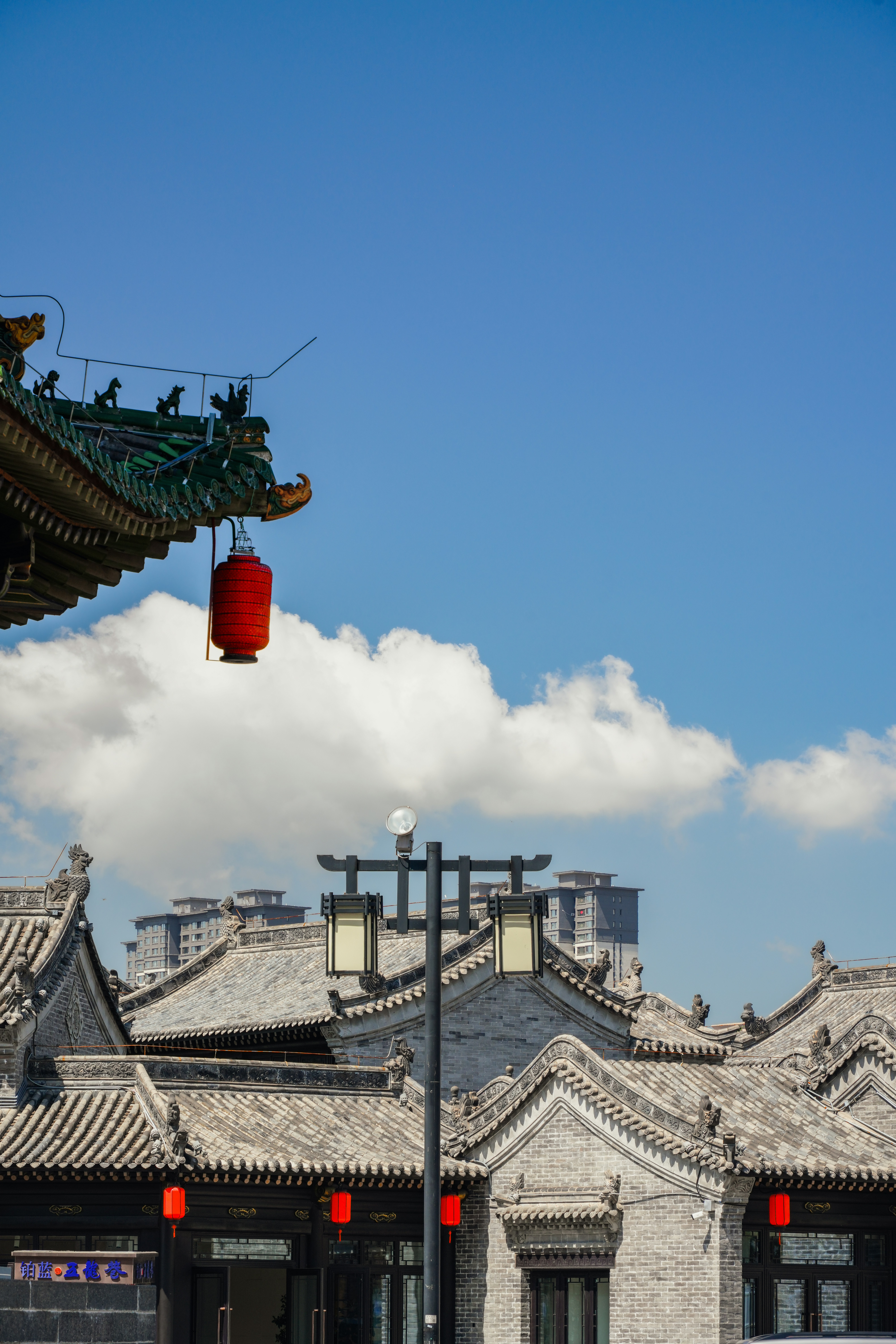 Traditional chinese architecture with red lanterns under blue sky.