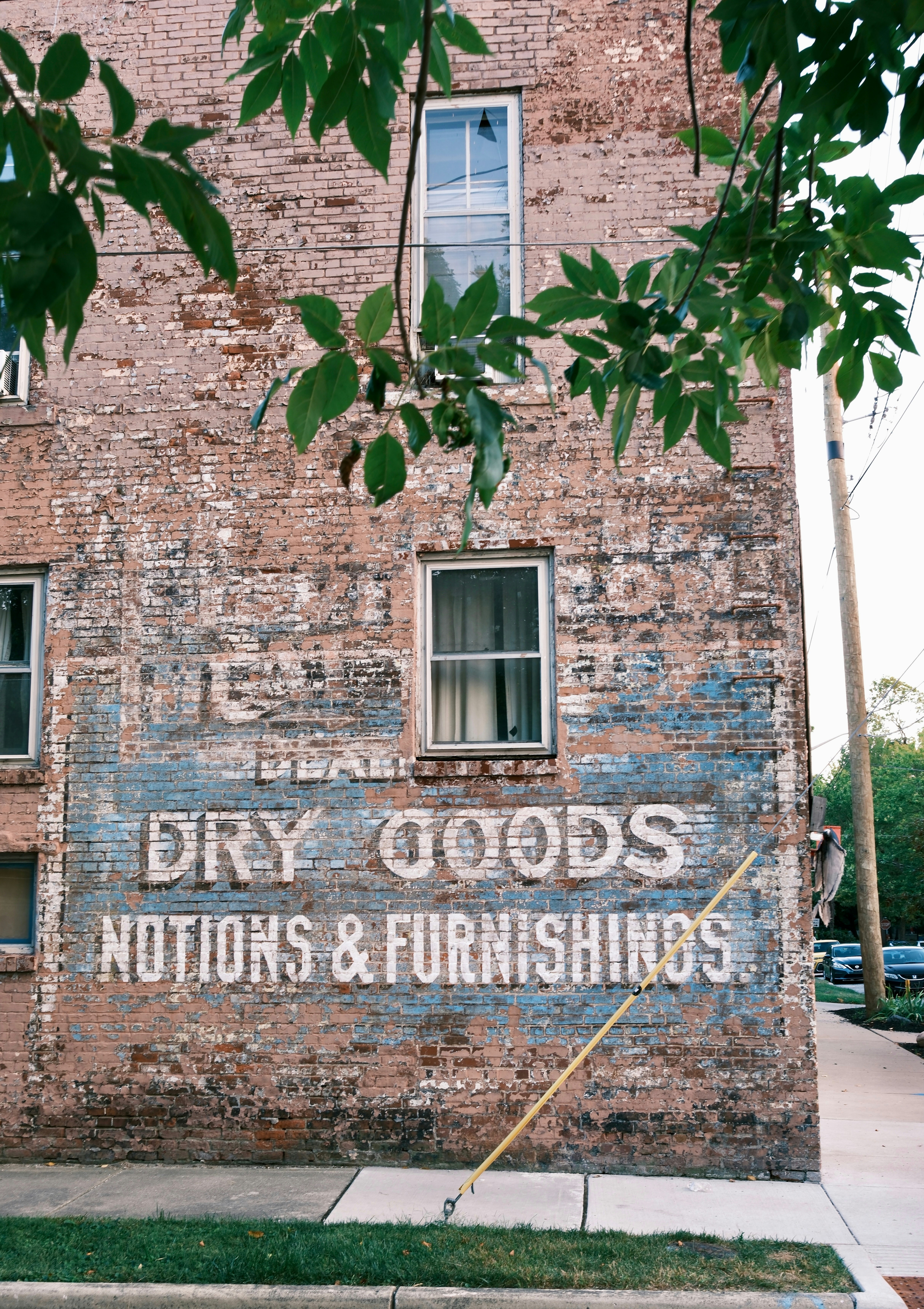 Weathered Dry Goods on a Brick Facade, Framed by Green Canopy