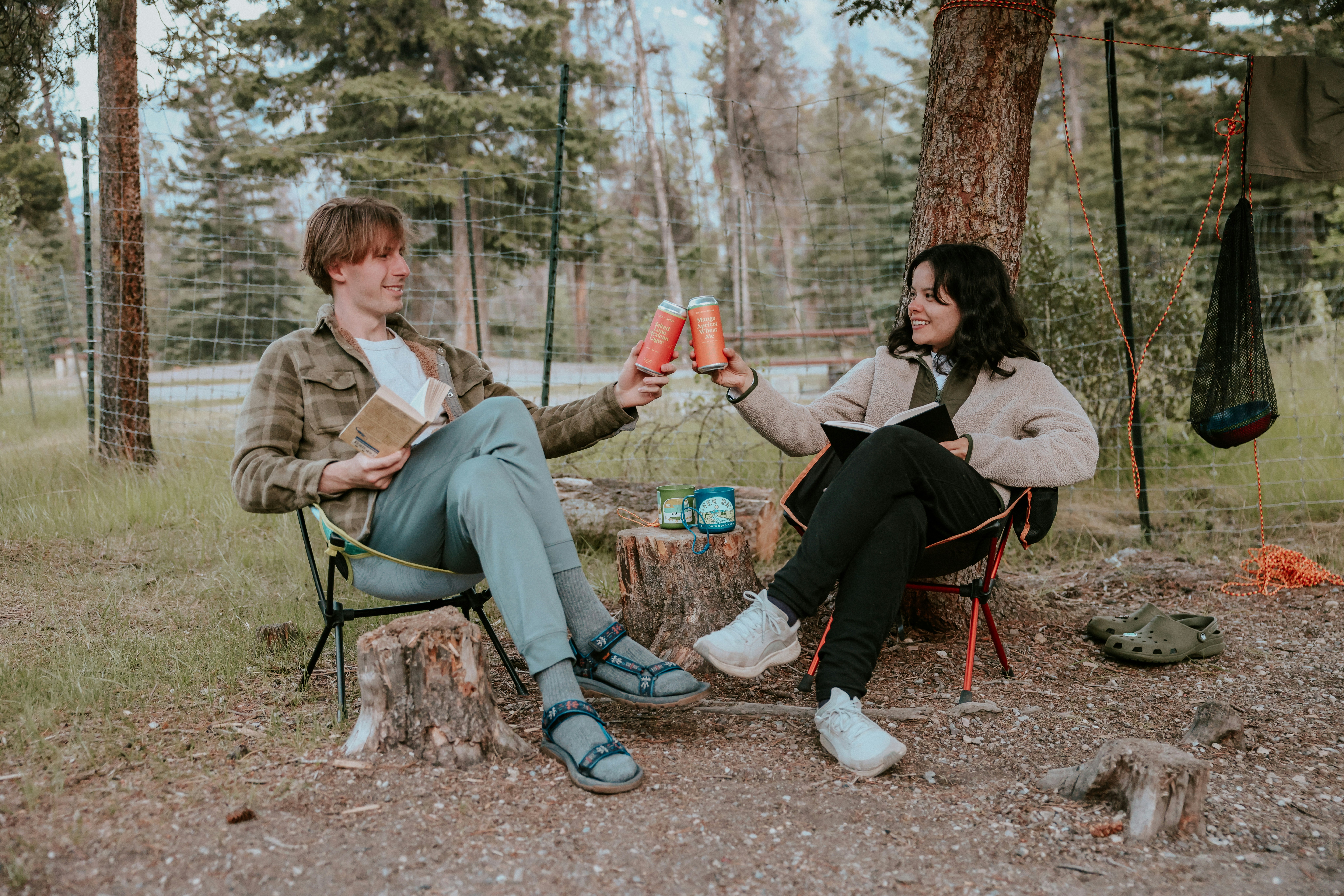 Couple toasting drinks while camping in the woods.