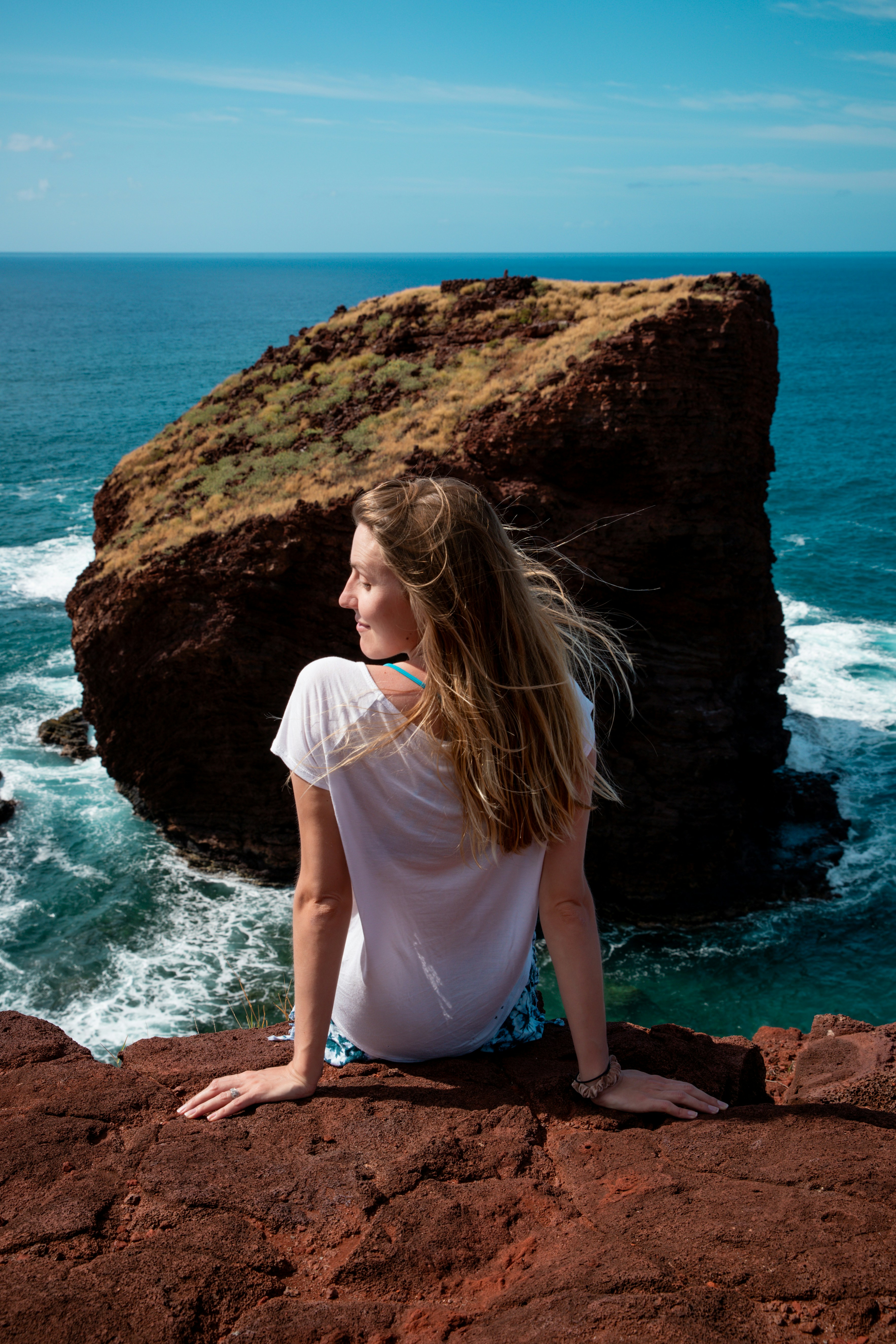 Lanai | Woman sitting on cliff overlooking ocean and rock formation