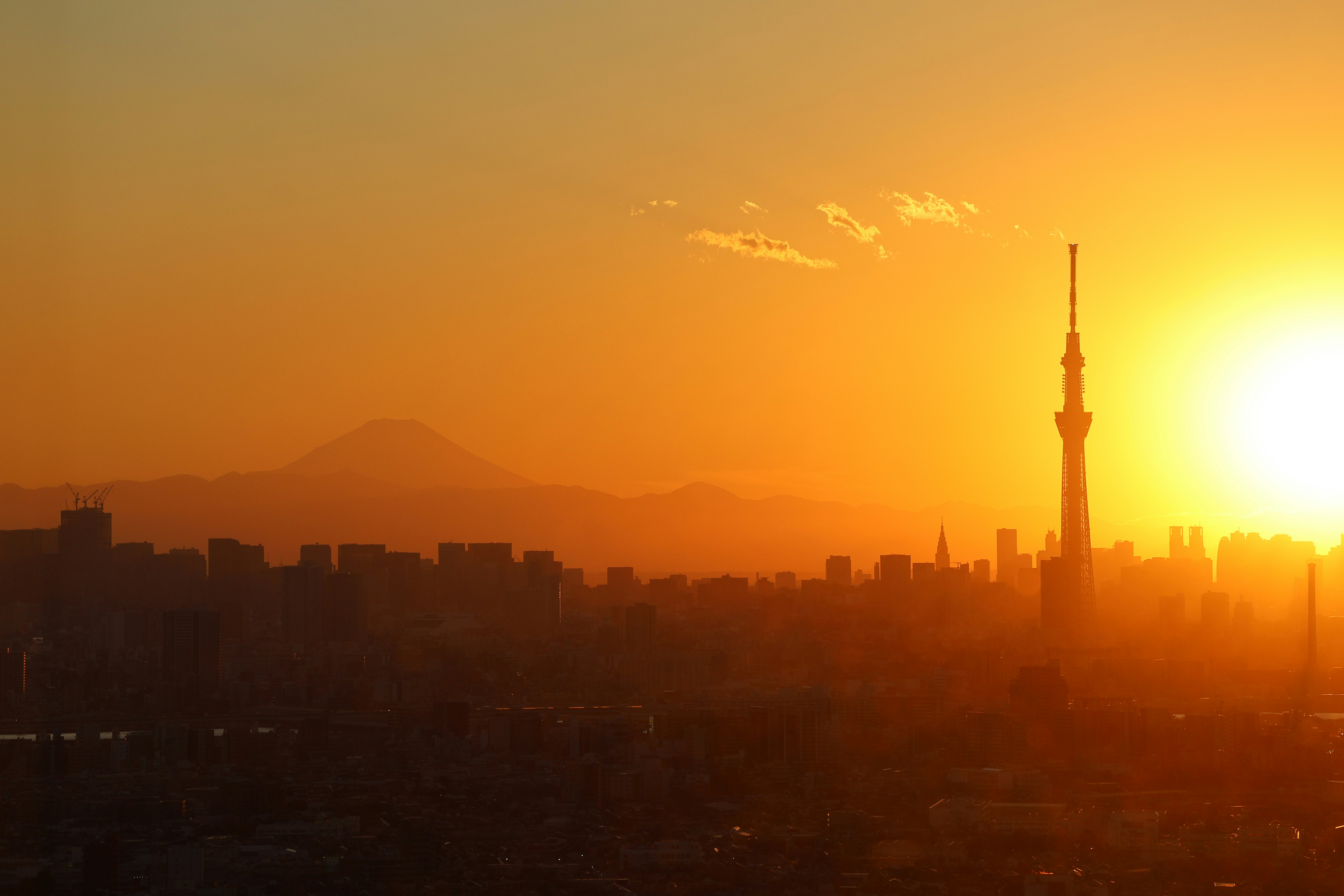 Sunset over a city skyline with a tall tower.