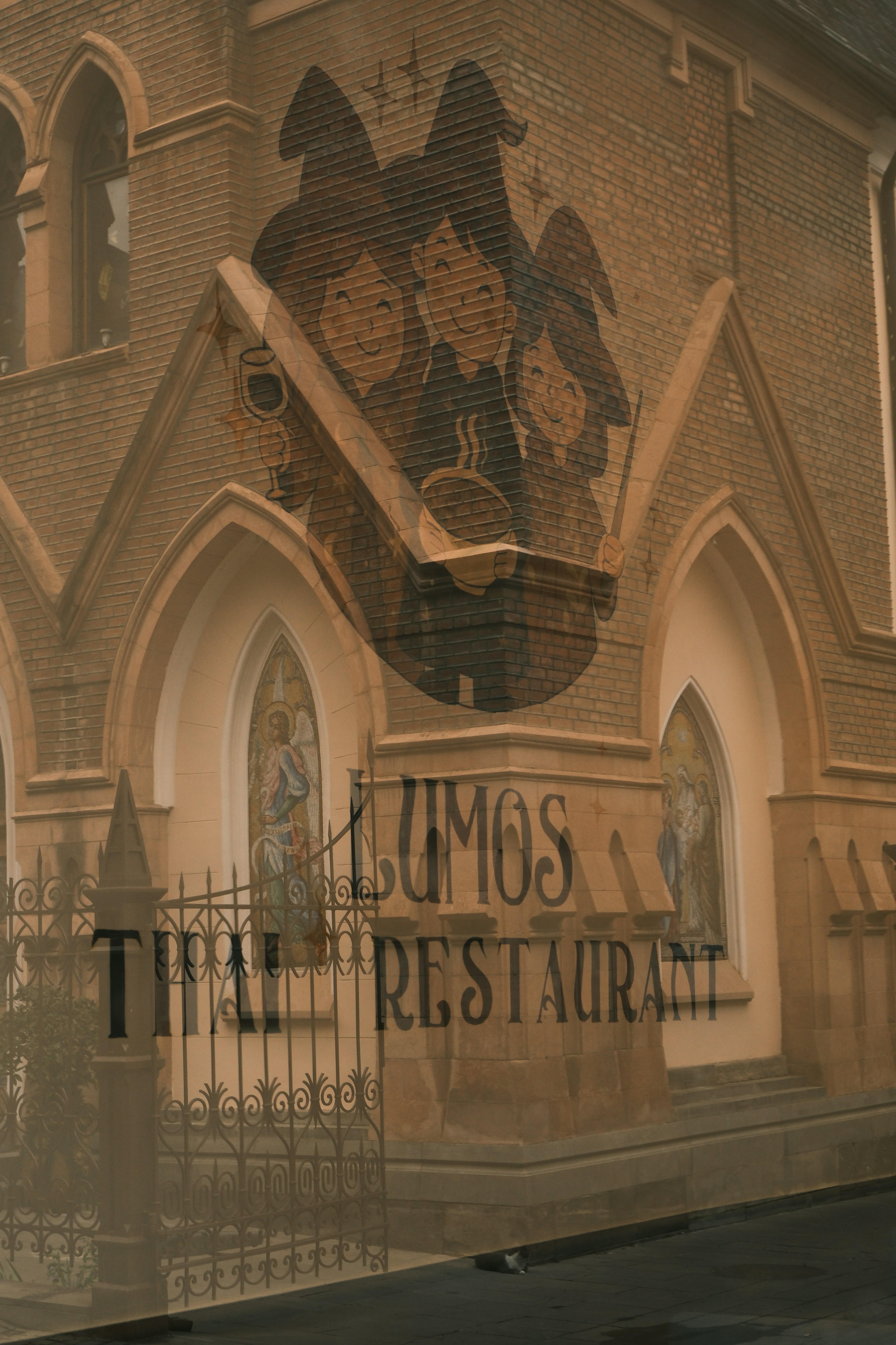 Building with "lumos restaurant" sign and witch art.
