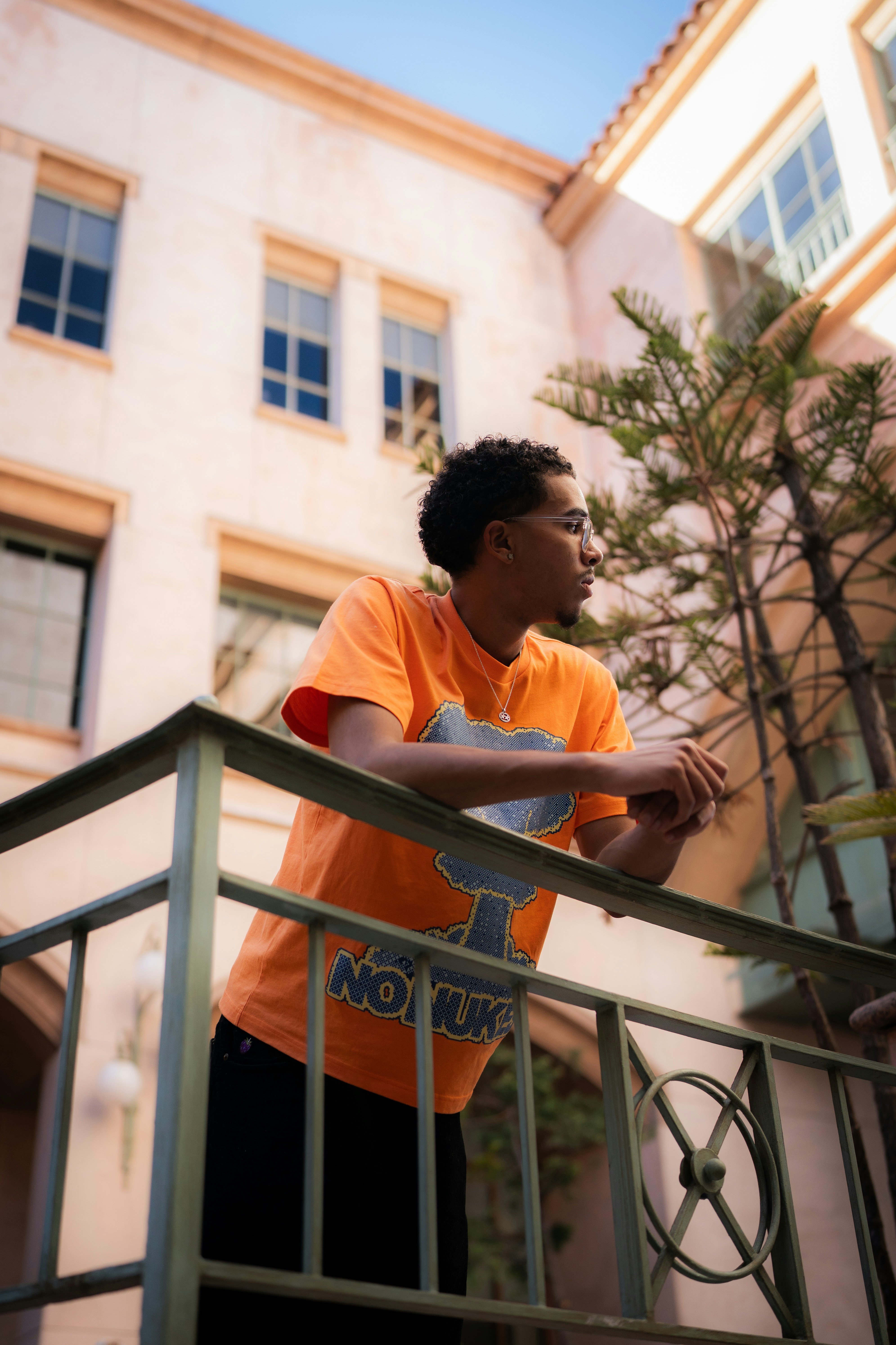 Portrait on the Balcony: Youthful Vigil Over a Sunlit Campus Courtyard