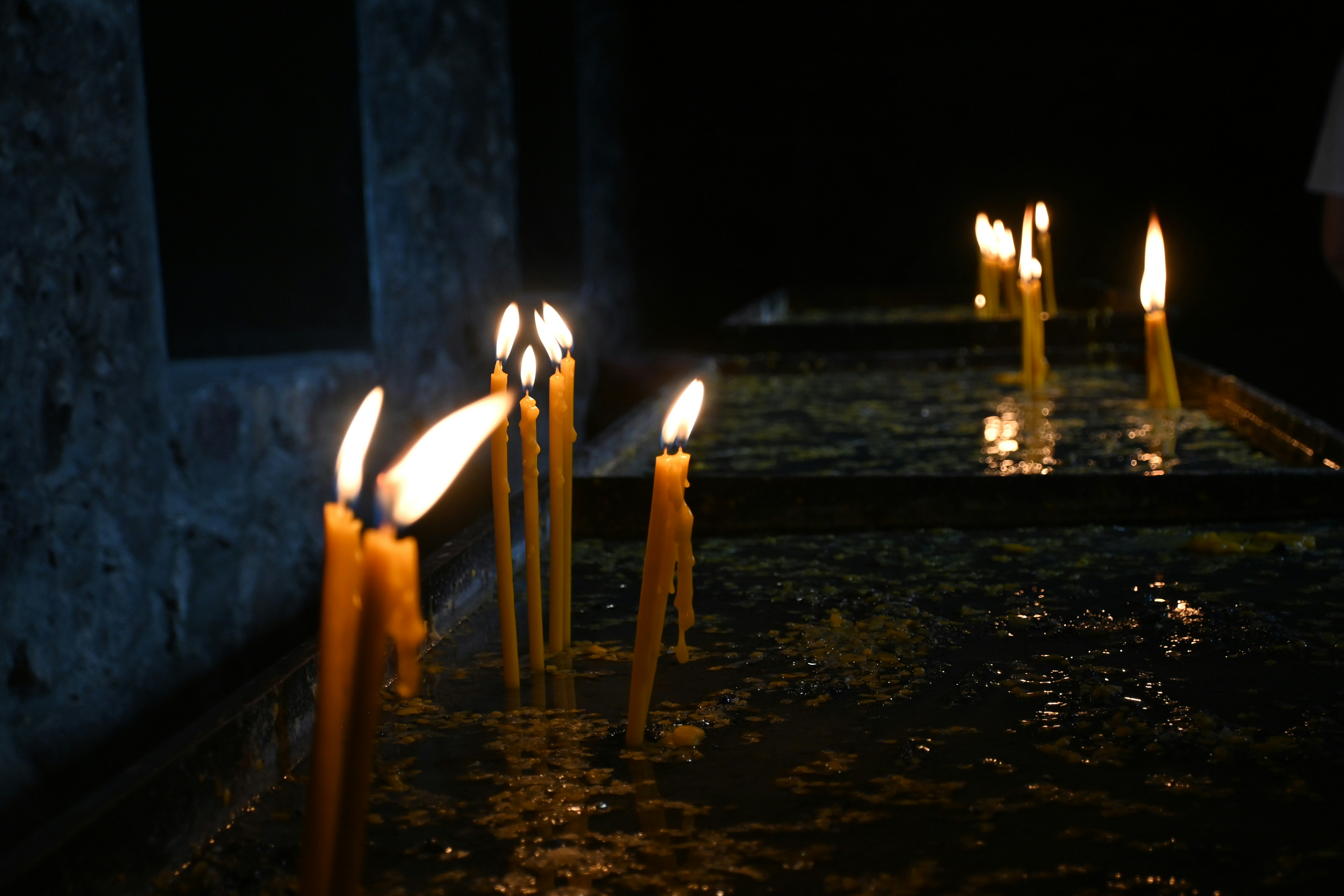Burning candles in dark water with reflections